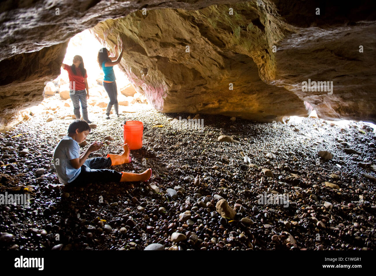Three children looking around in a sea cave Stock Photo - Alamy