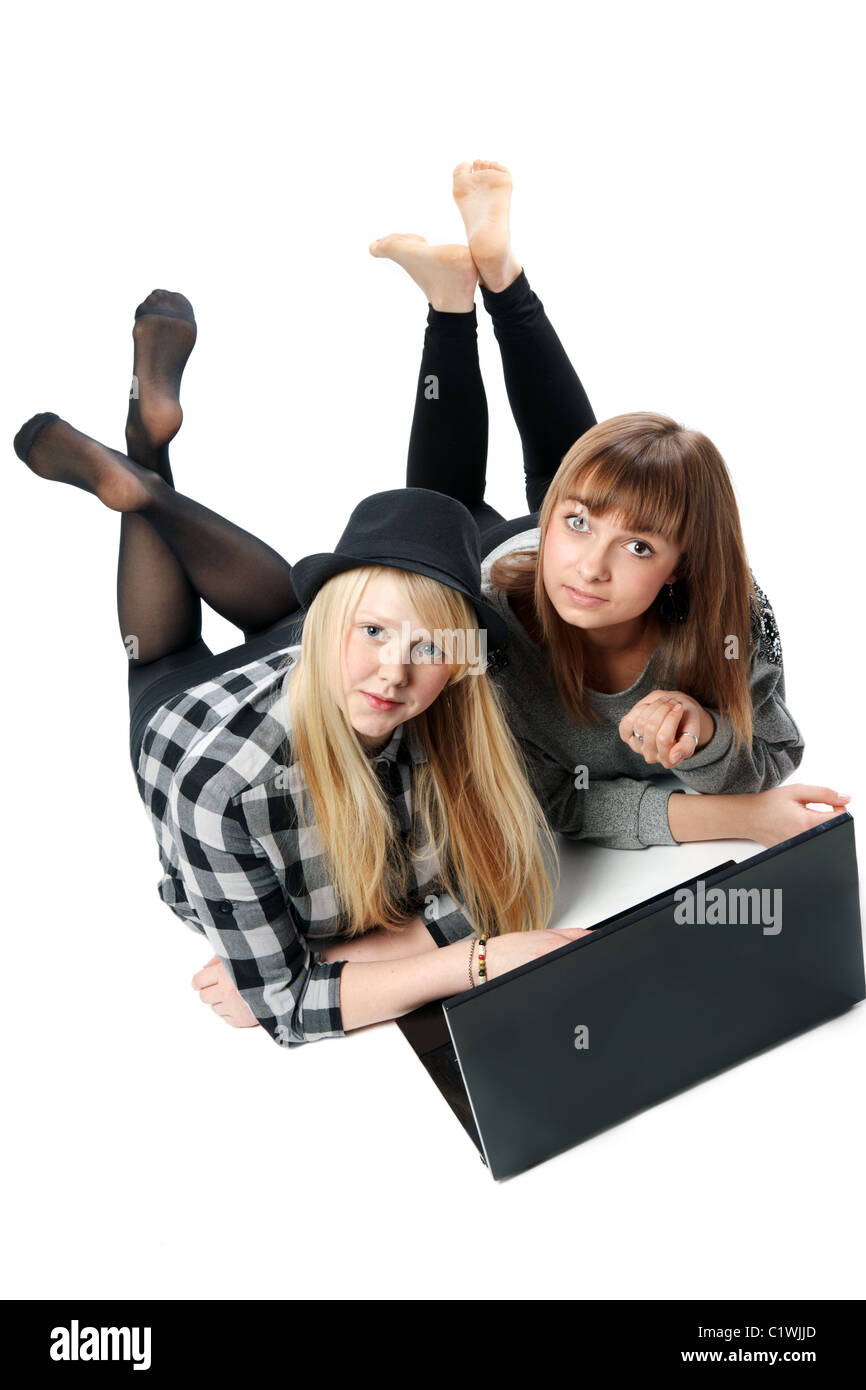 Two girls lies with computer on white background Stock Photo - Alamy