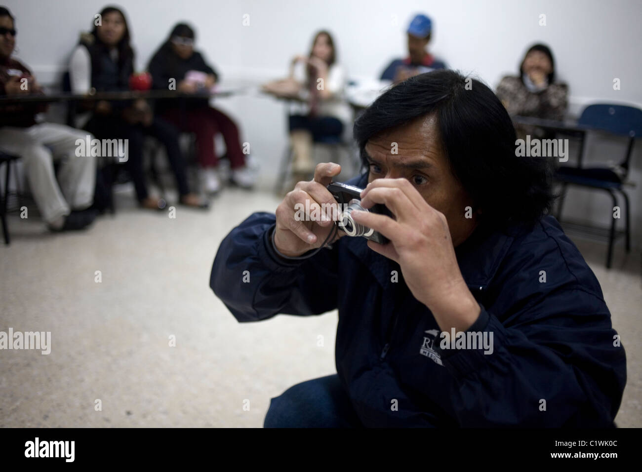 A blind photographer takes pictures as he kneels at a photography ...