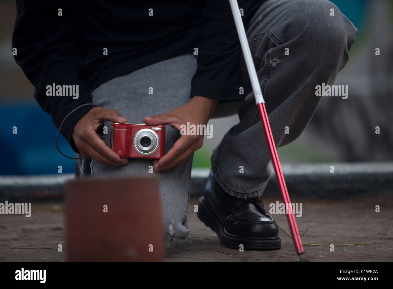 A blind photographer takes pictures as he kneels during a photography ...