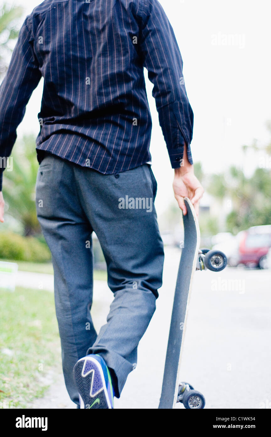 Rear view of a man holding a skateboard Stock Photo - Alamy