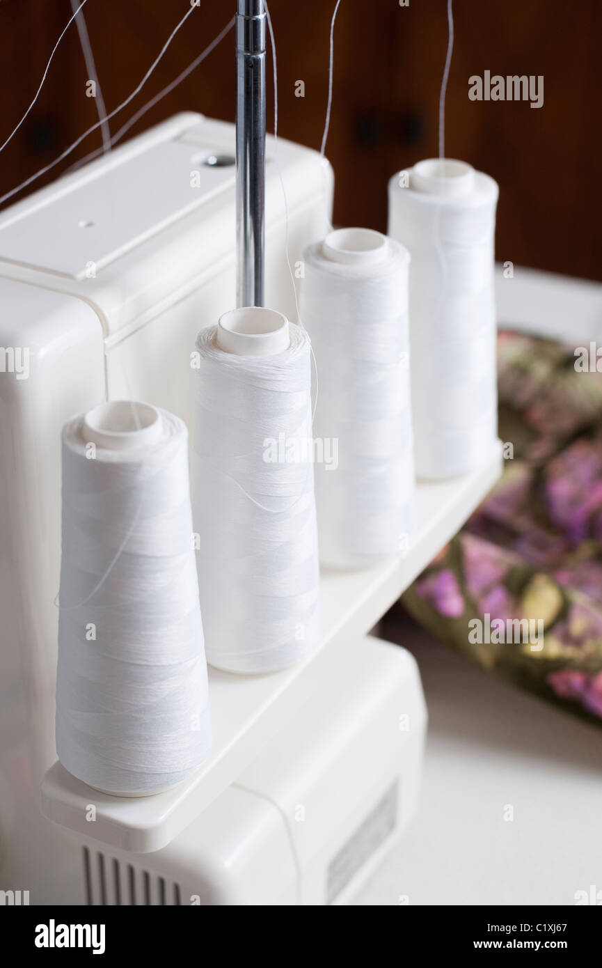 Serger with white thread spools Stock Photo - Alamy