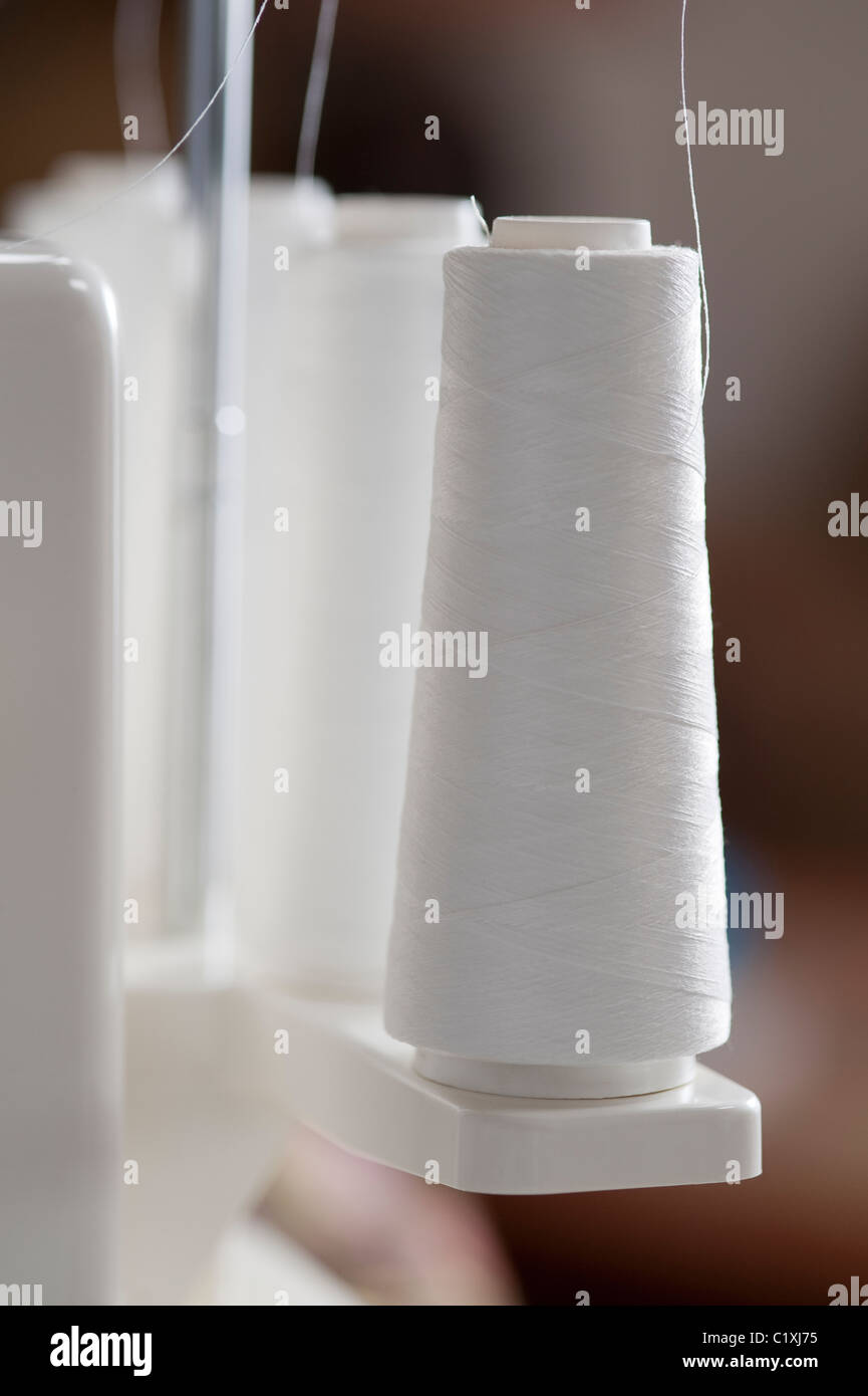 Serger with white thread spools Stock Photo - Alamy