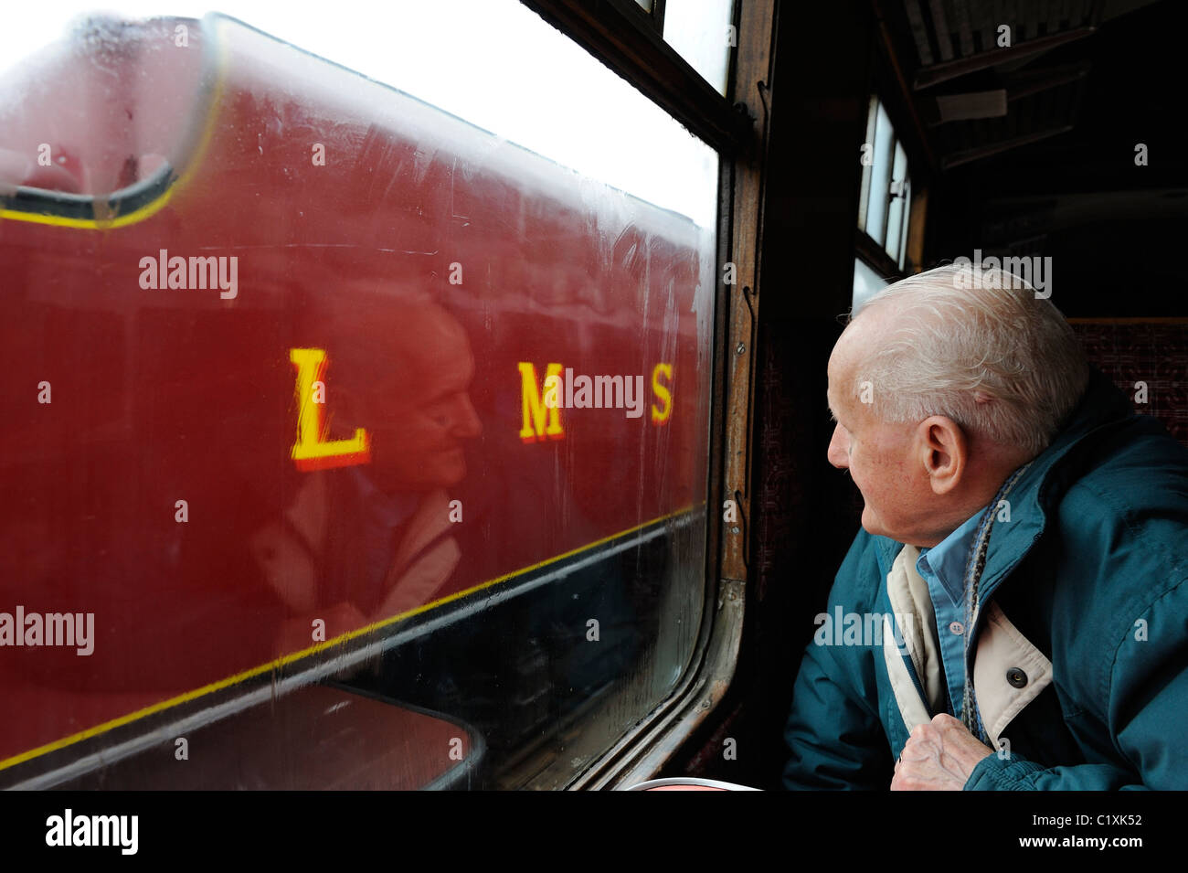 pensioner looking out of train window at passing steam train great ...