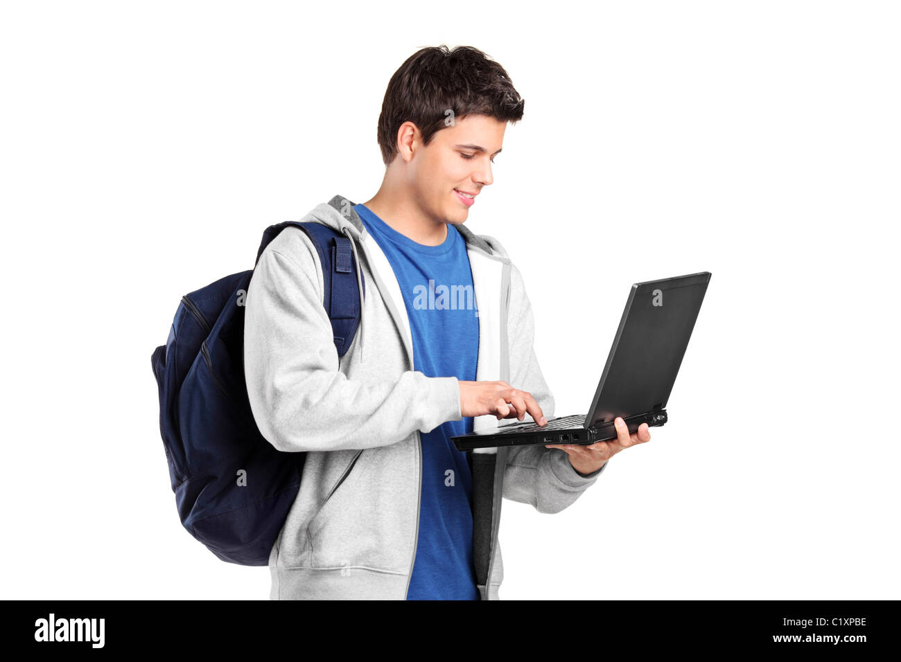 A portrait of a male student with a school bag working on a laptop ...