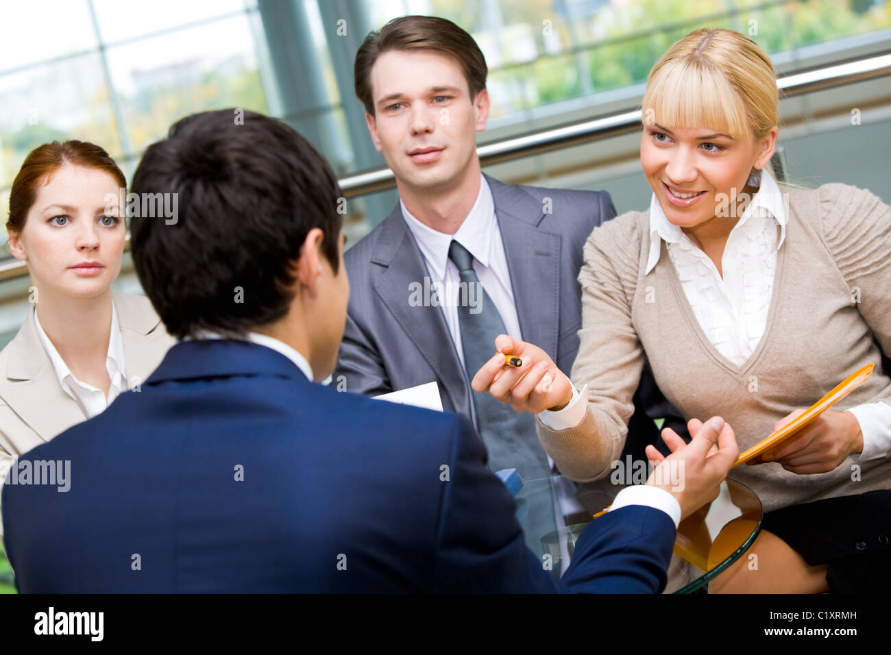 Several specialists looking at businessman during interview Stock Photo ...