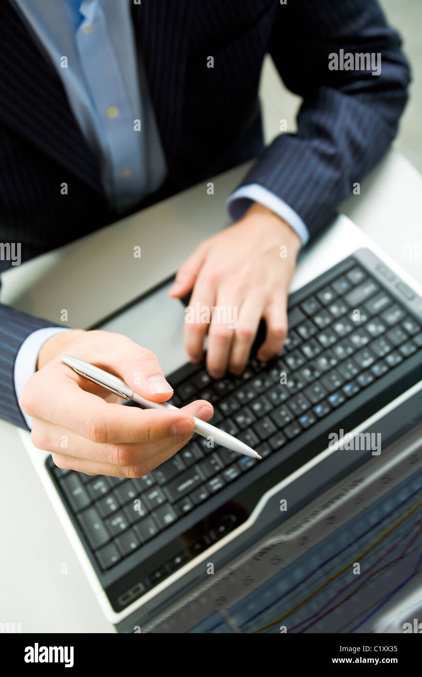 Above angle of male hand with pen pointing at laptop screen on ...