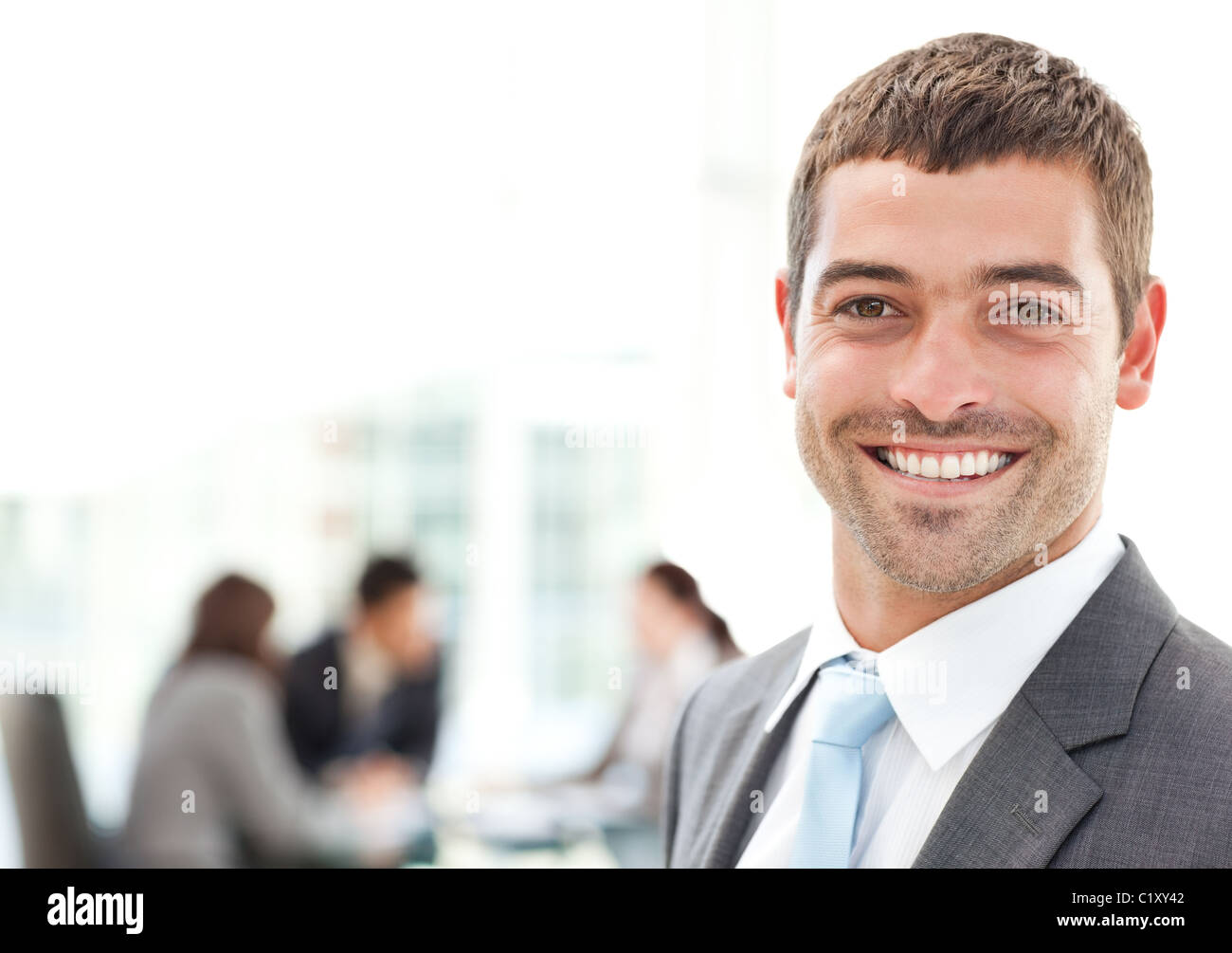 Businessman smiling at the camera while his team is working Stock Photo ...