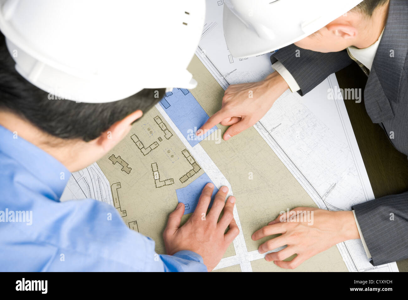 Above view of engineers looking at blueprints with sketches of projects ...