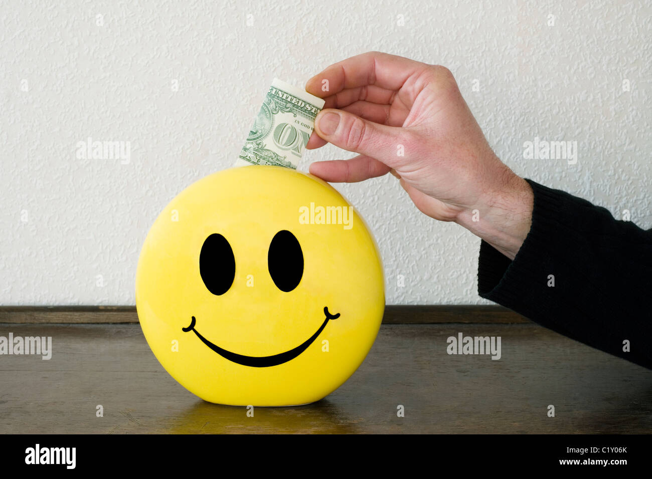 man putting money into a smiley savings box Stock Photo - Alamy