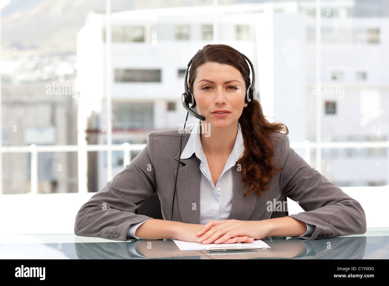 Attractive businesswoman speaking using headset sitting at a table ...