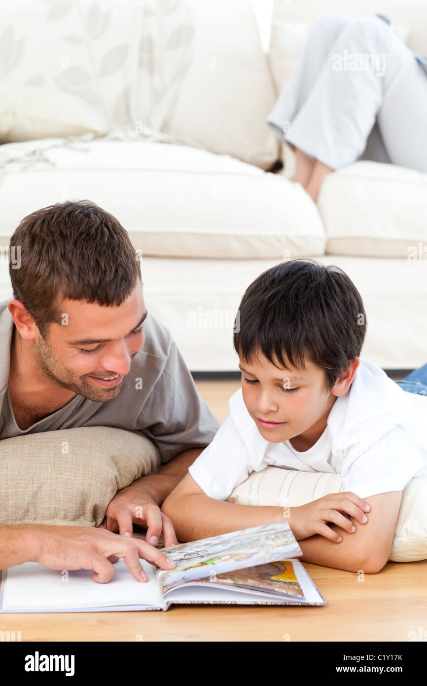 Attentive father reading a book with his son lying on the floor Stock ...