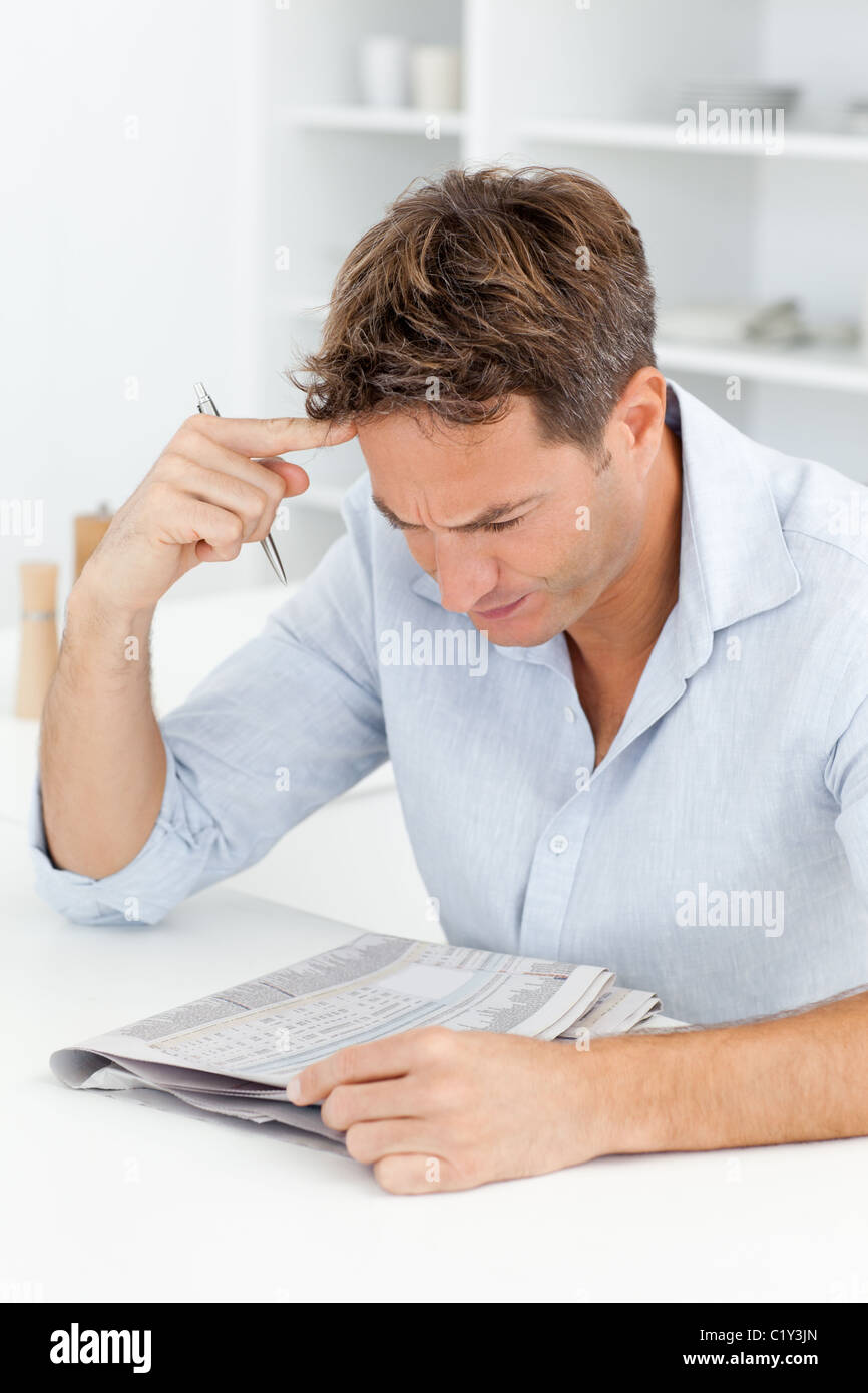 Concentrated man doing a cryptic crossword sitting in his kitchen Stock ...