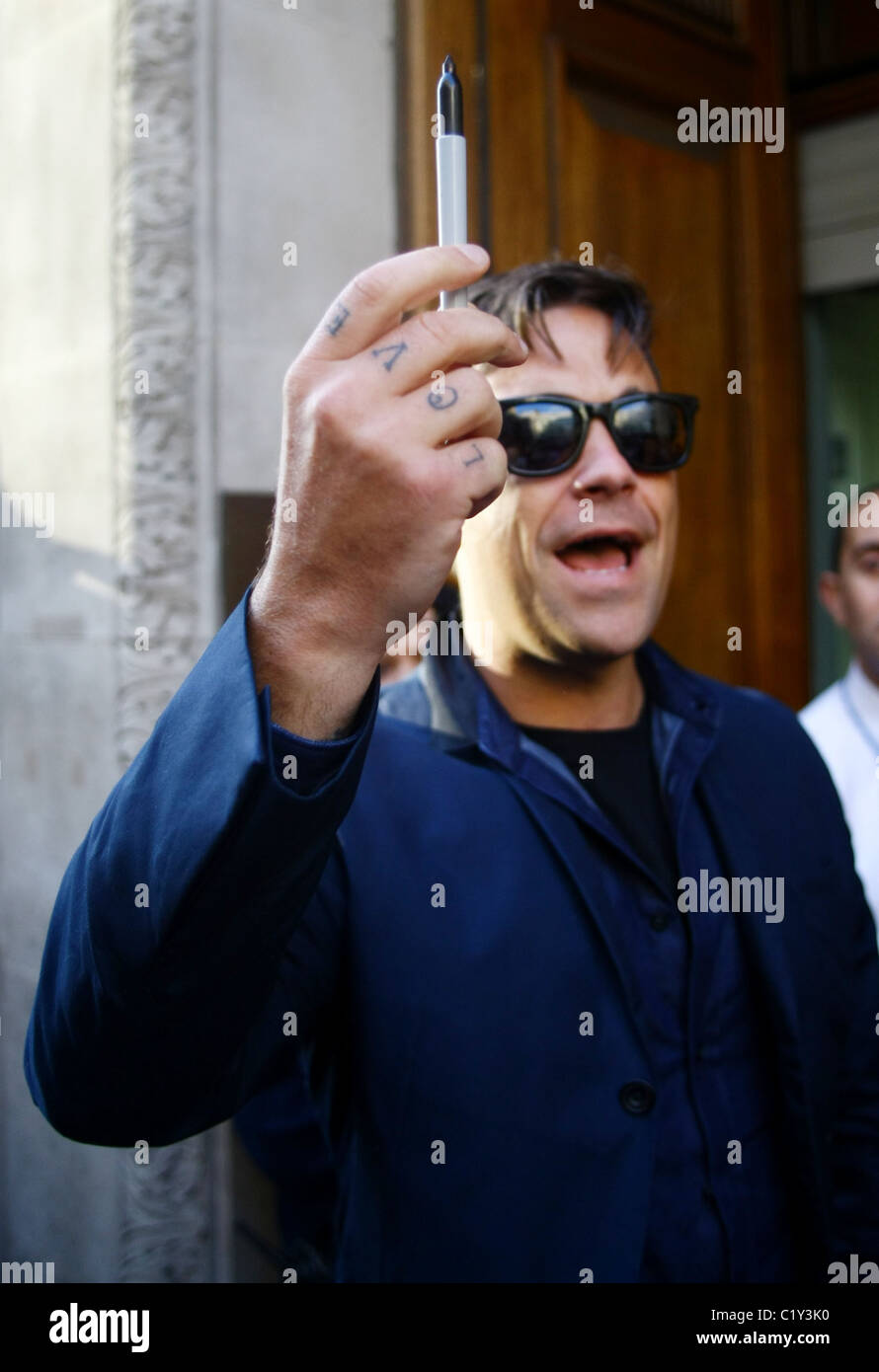 Robbie Williams signing autographs for fans as he arrives at Radio one ...