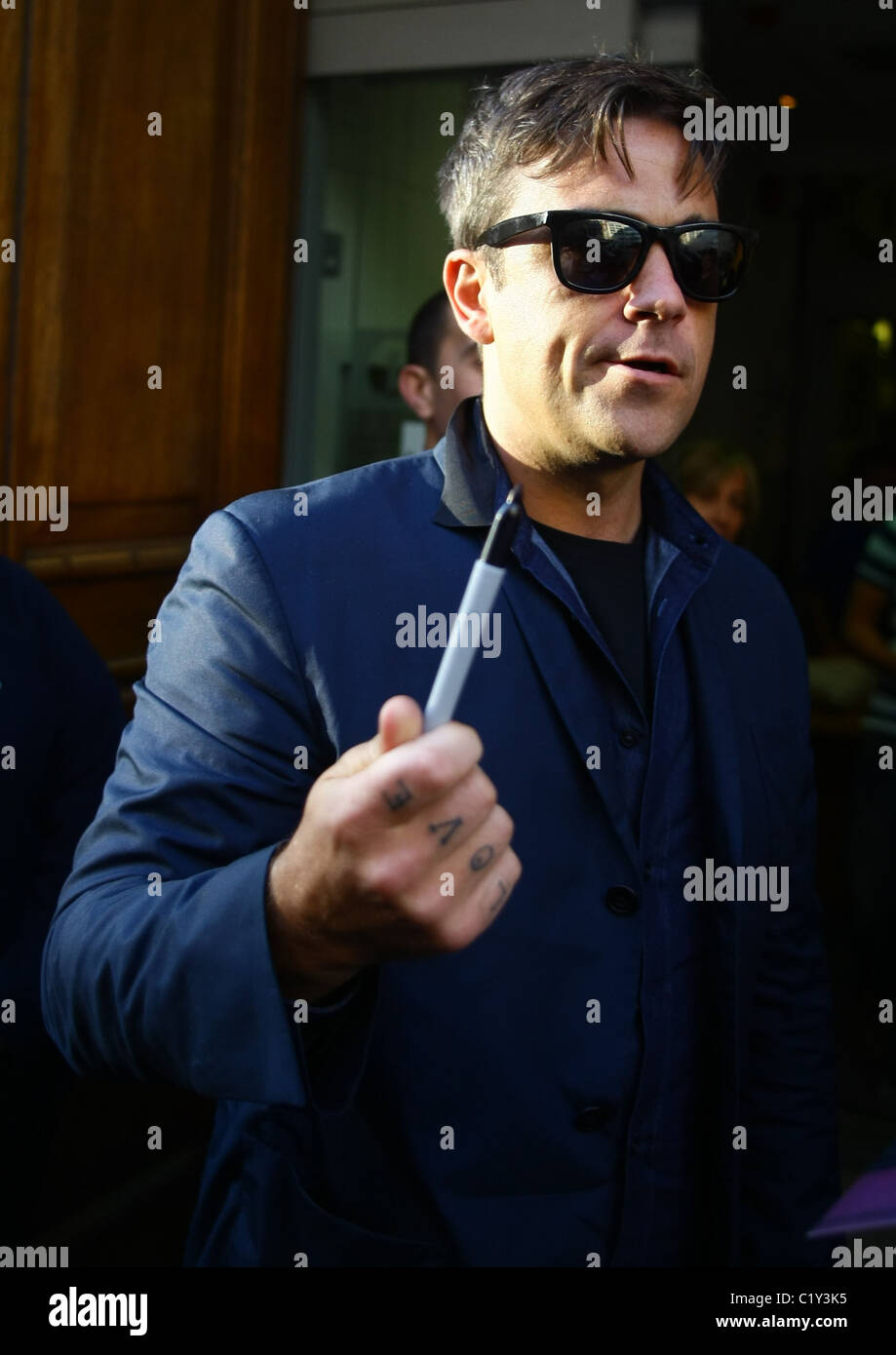 Robbie Williams signing autographs for fans as he arrives at Radio one ...