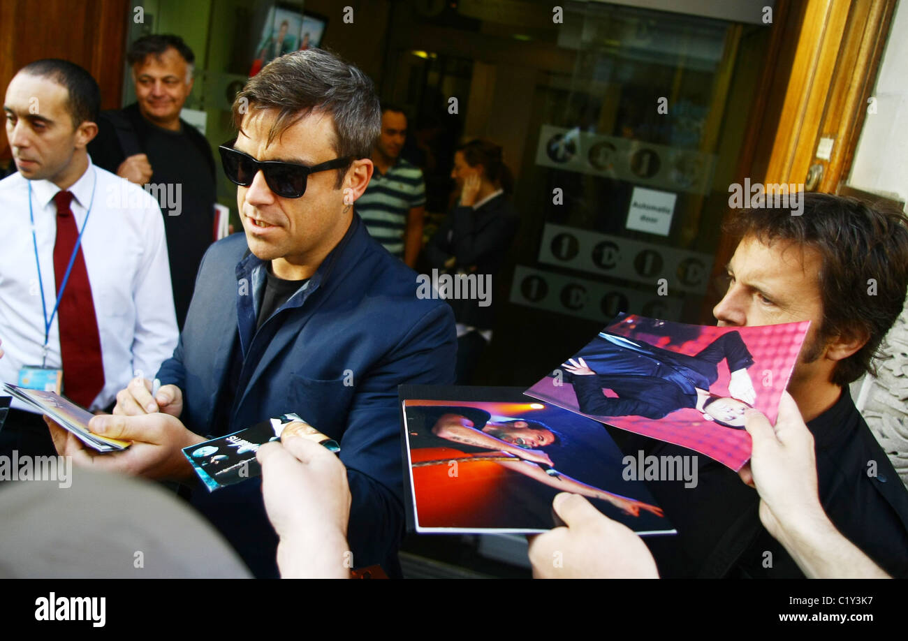 Robbie Williams signing autographs for fans as he arrives at Radio one ...