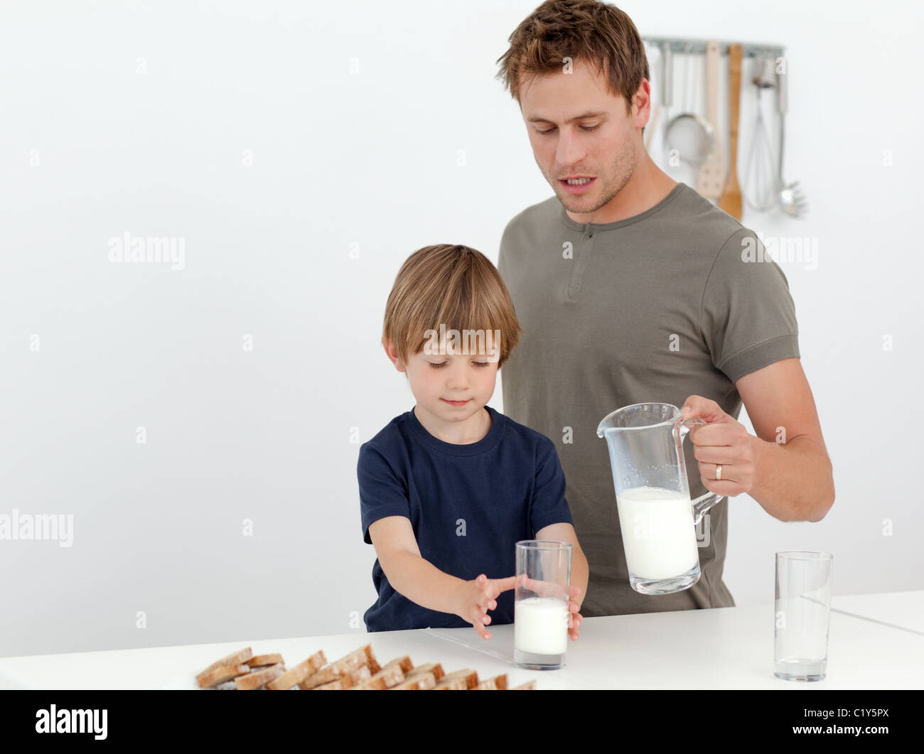 Handsome man giving milk to his son Stock Photo - Alamy
