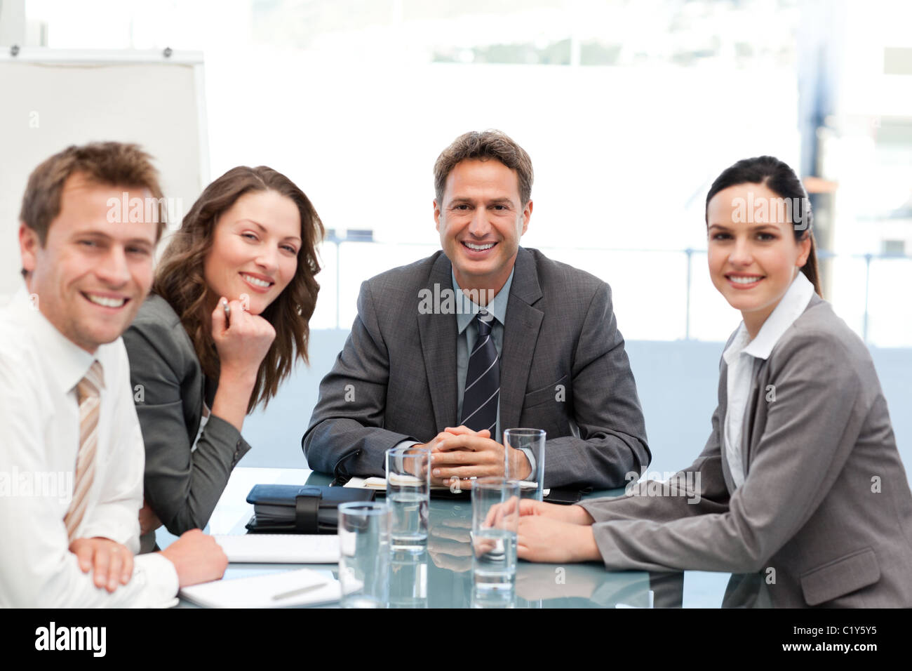 Portrait of a positive team sitting at a table Stock Photo - Alamy