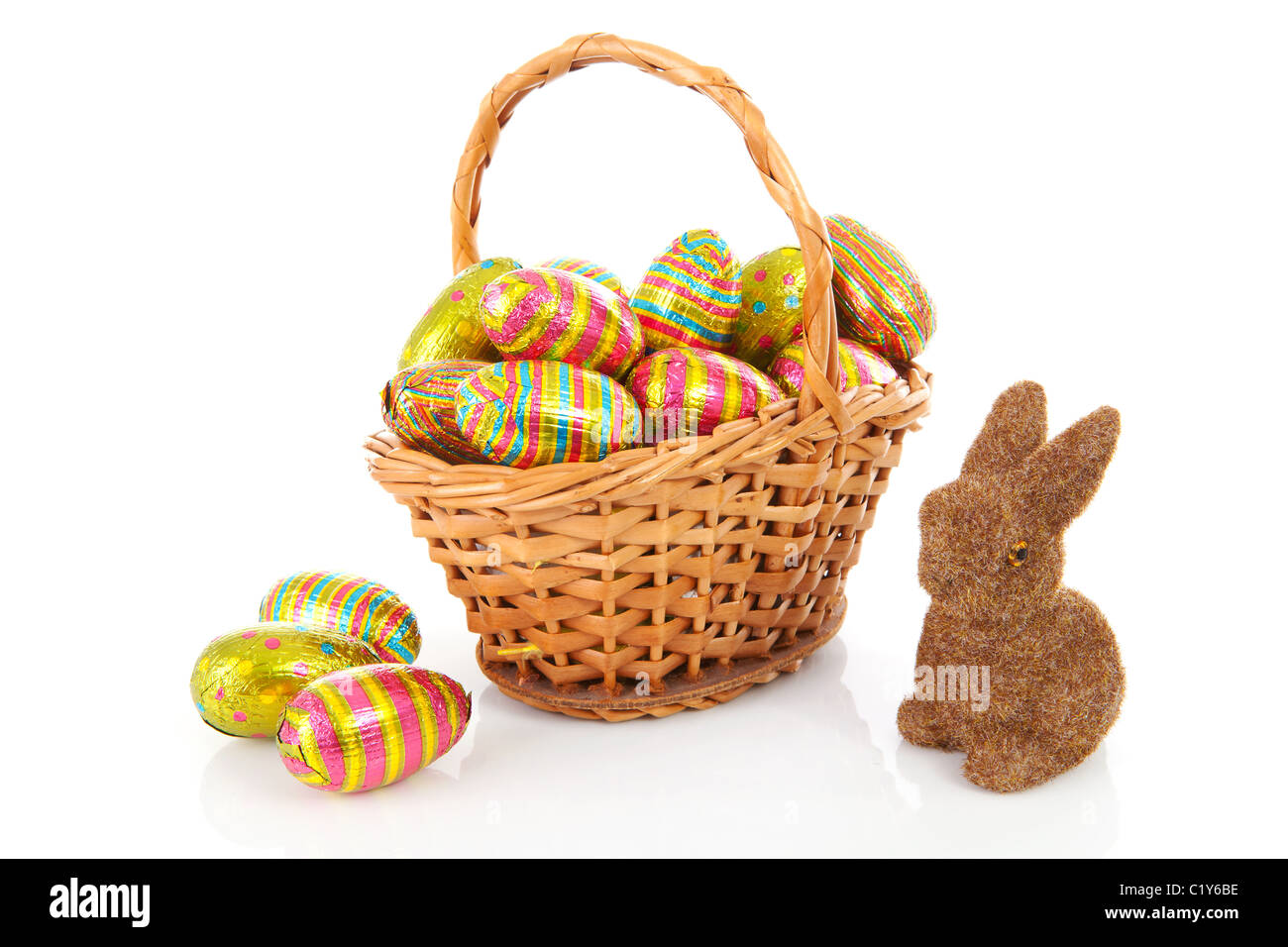 Cane basket with colorful easter eggs and bunny over white background ...