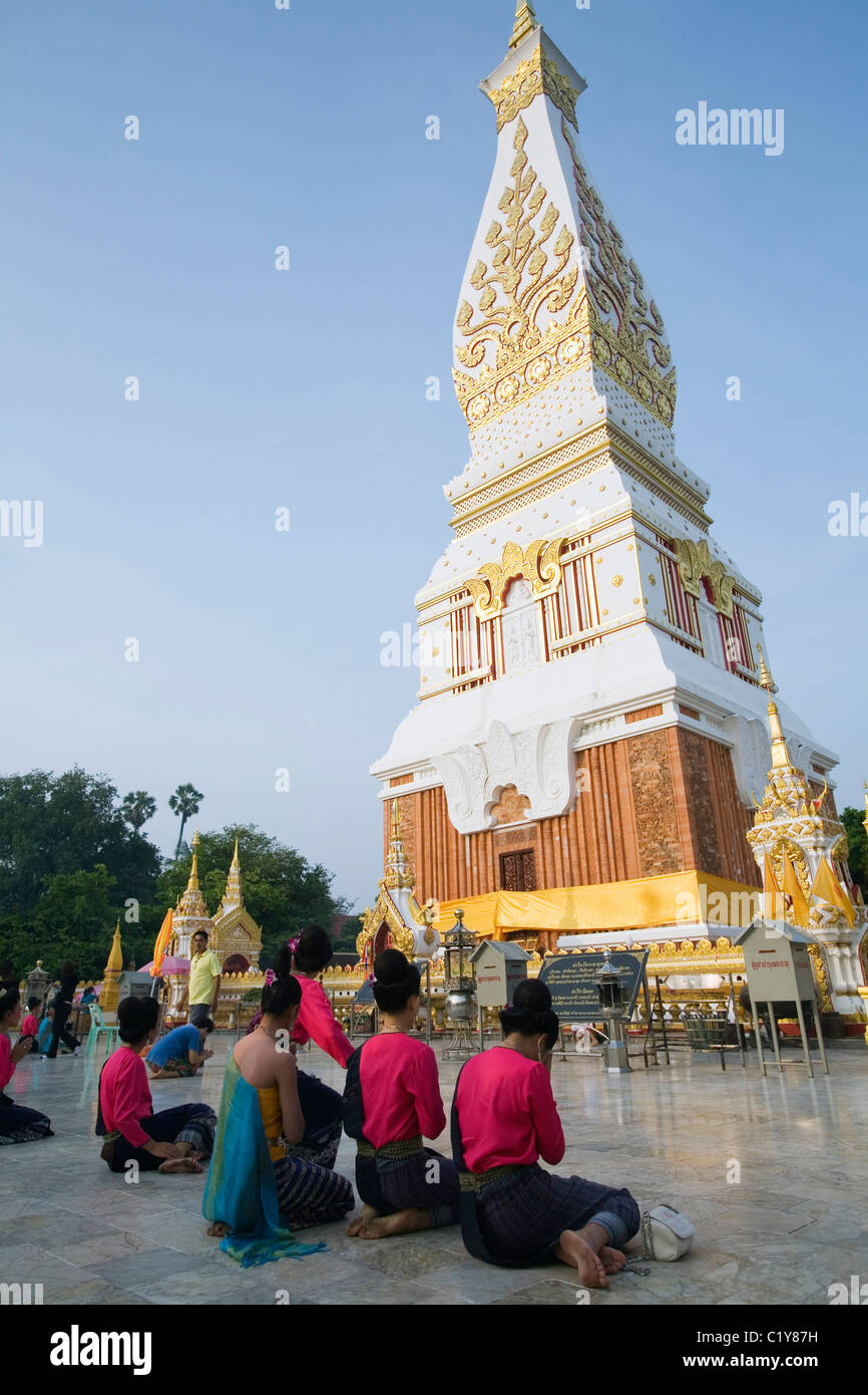 Pilgrims kneel at the foot of the revered chedi at Wat Phra That Phanom ...