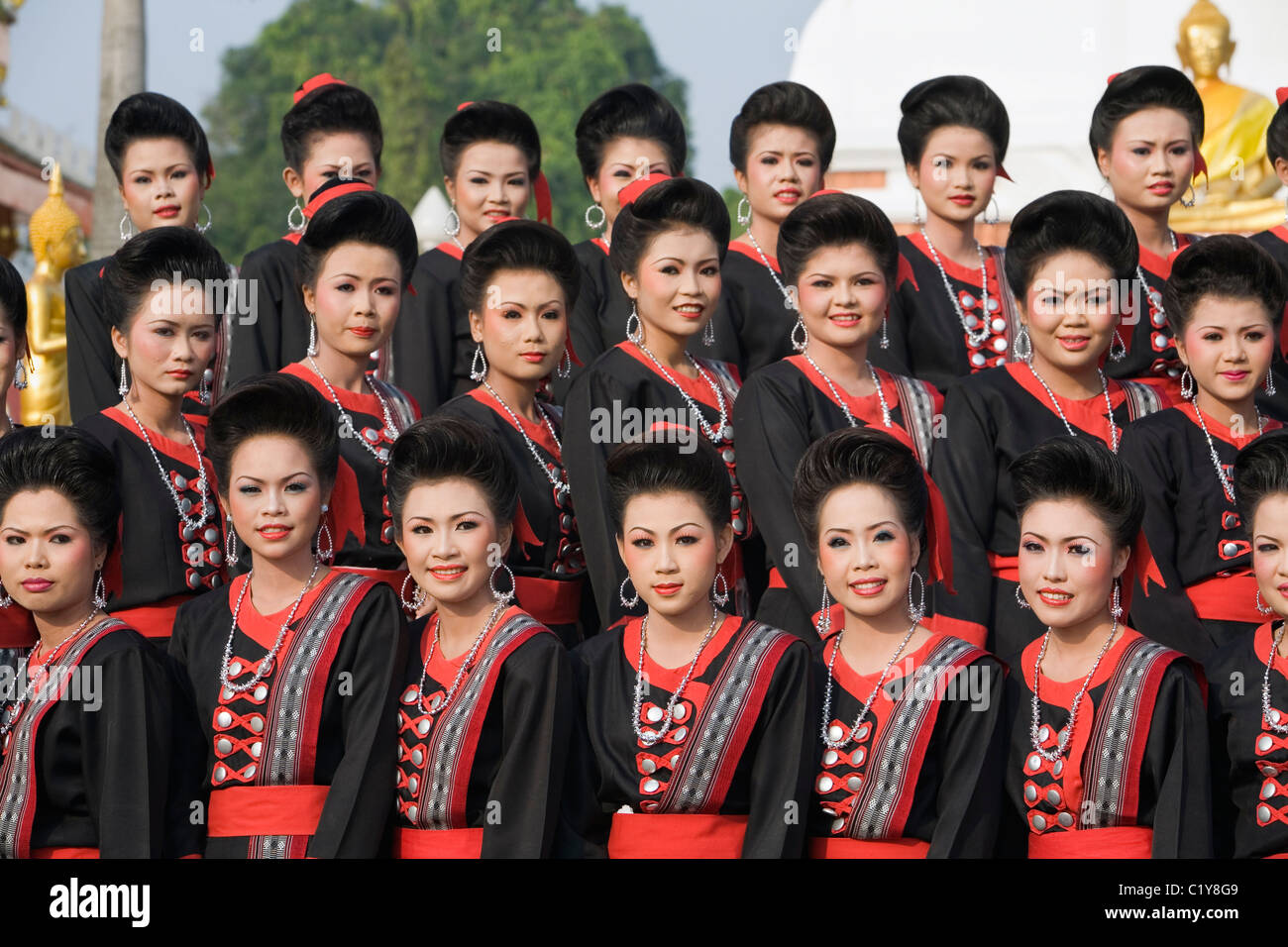 Young dancers adorned in traditional Isan dress sit in front of Wat ...