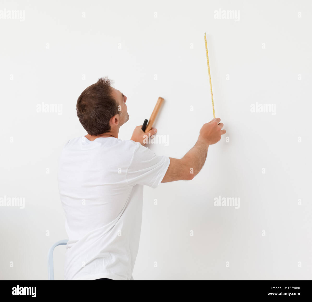Handsome man looking at a wall with ruler and tools Stock Photo - Alamy