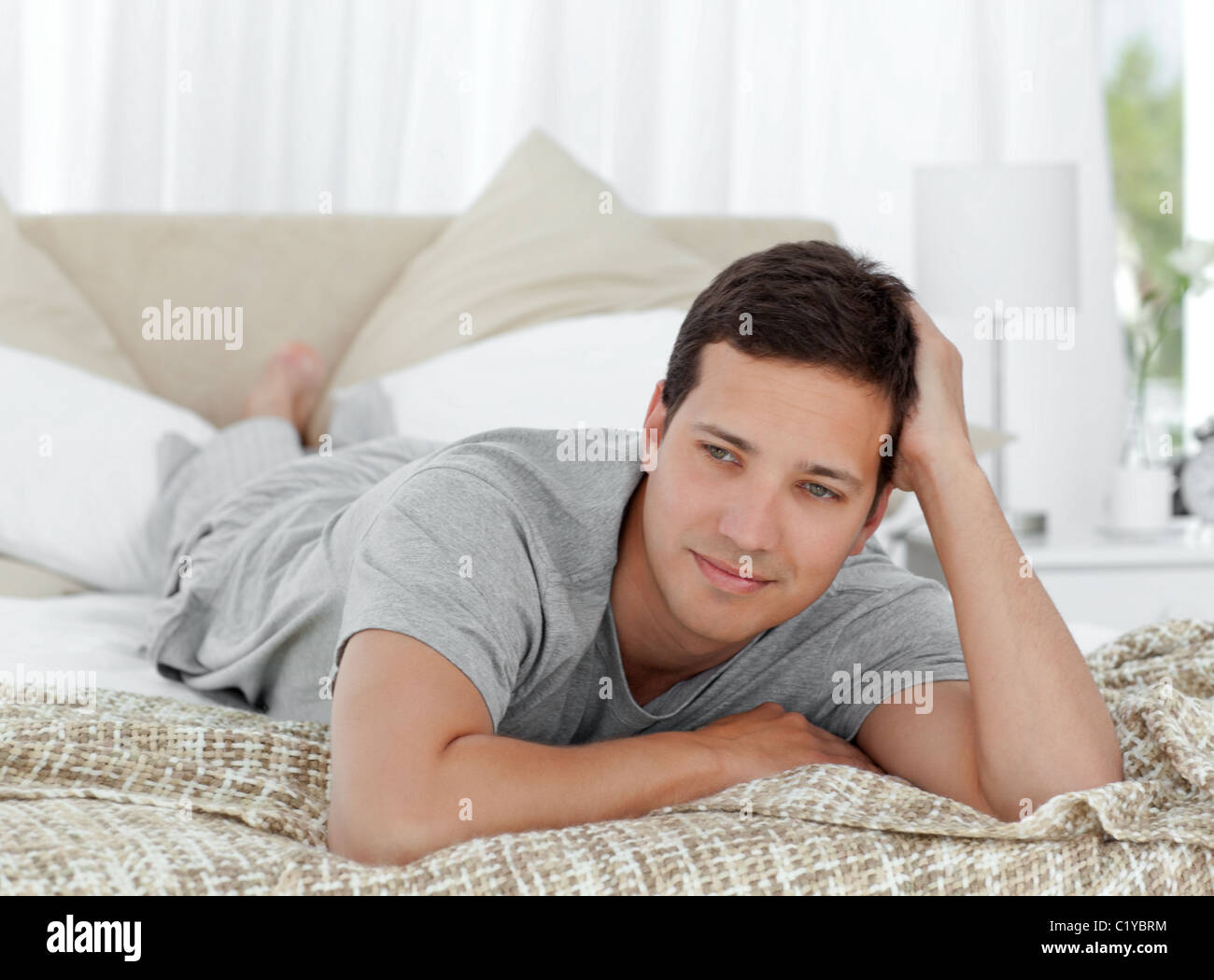 Thoughtful young man lying on his bed Stock Photo - Alamy