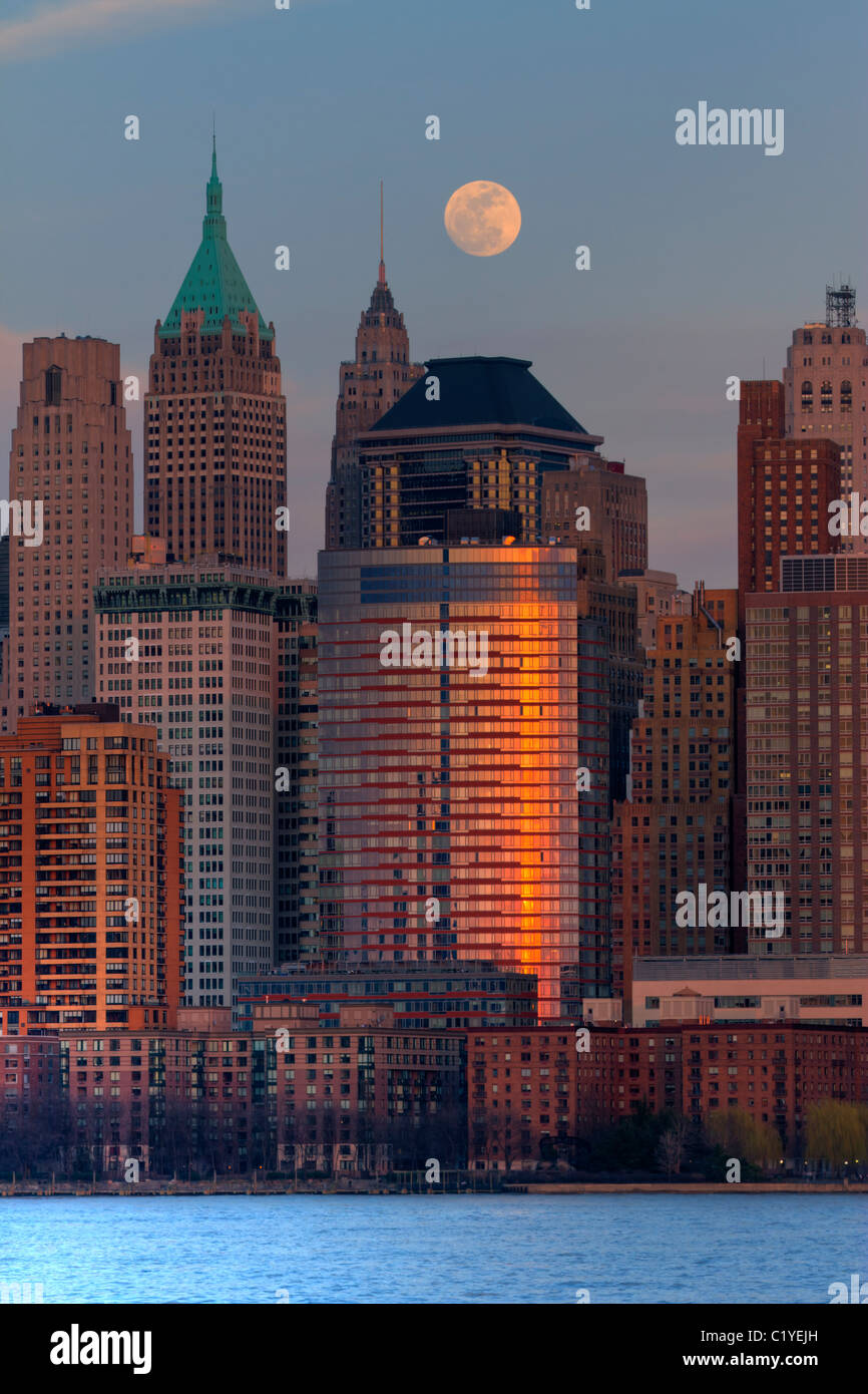A full moon rising over lower Manhattan at sunset seen from New Jersey ...