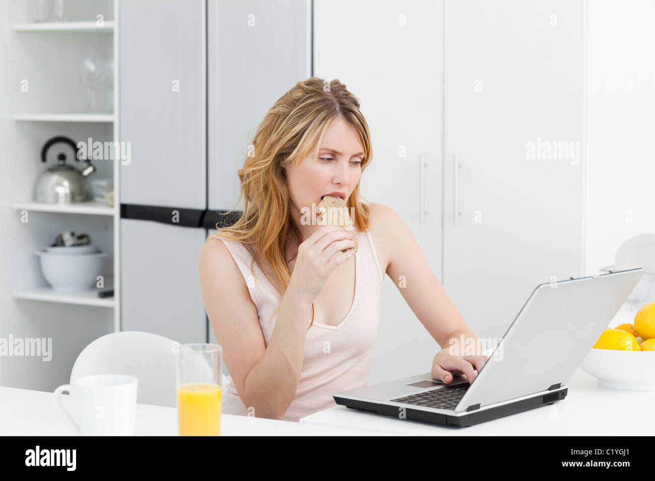 Woman drinking while she is looking at her laptop Stock Photo - Alamy