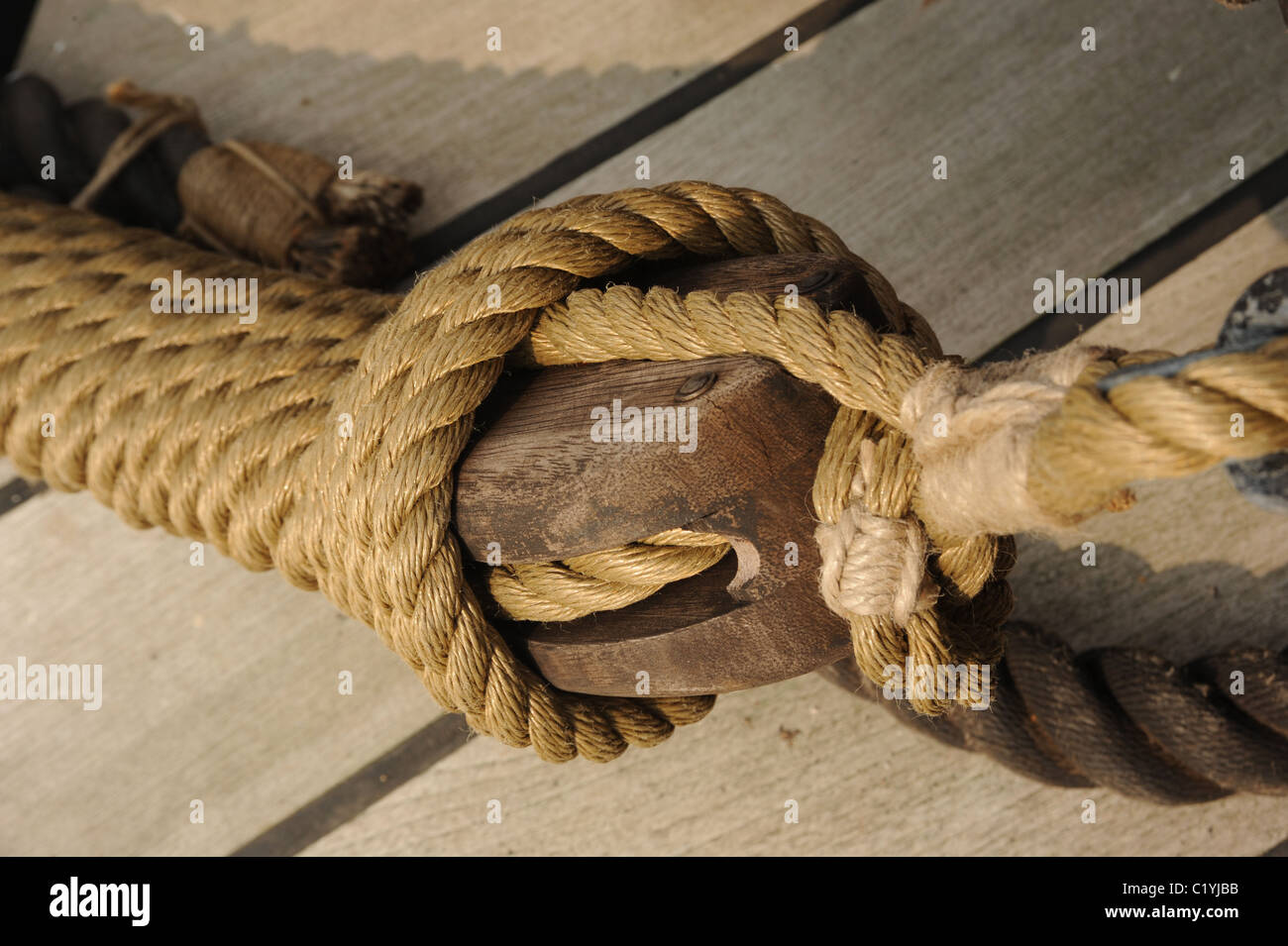Detail of a ships rigging. A wooden block and hemp rope against a teak ...