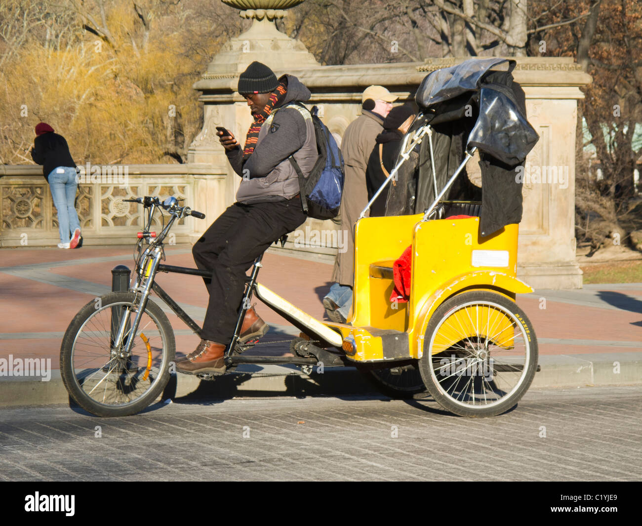 Pedicab driver in New York City's Central Park checks his messages on a ...