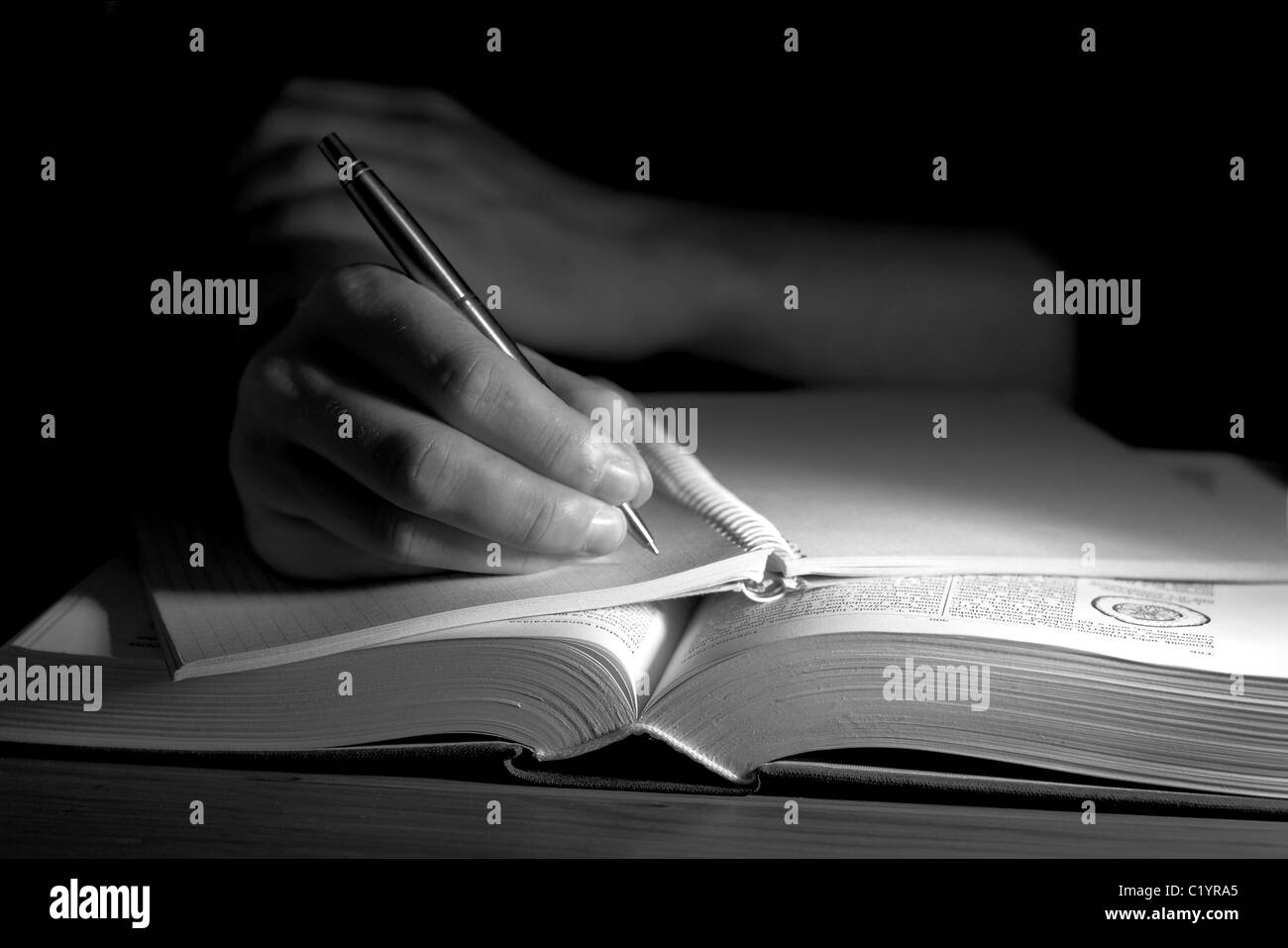 Open book in a dark room, with human hand taking notes Stock Photo - Alamy