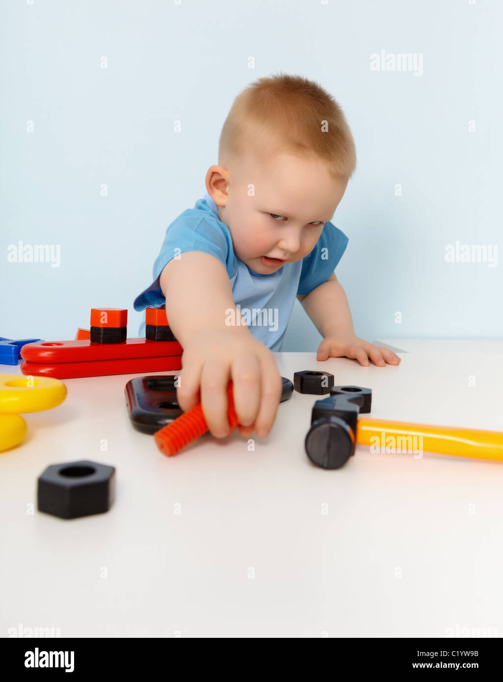 Little boy playing with a toy plastic constructor on blue background ...