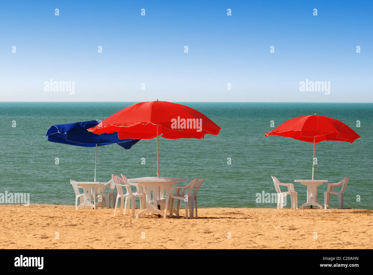 Table, chairs and parasol on the beach Stock Photo - Alamy
