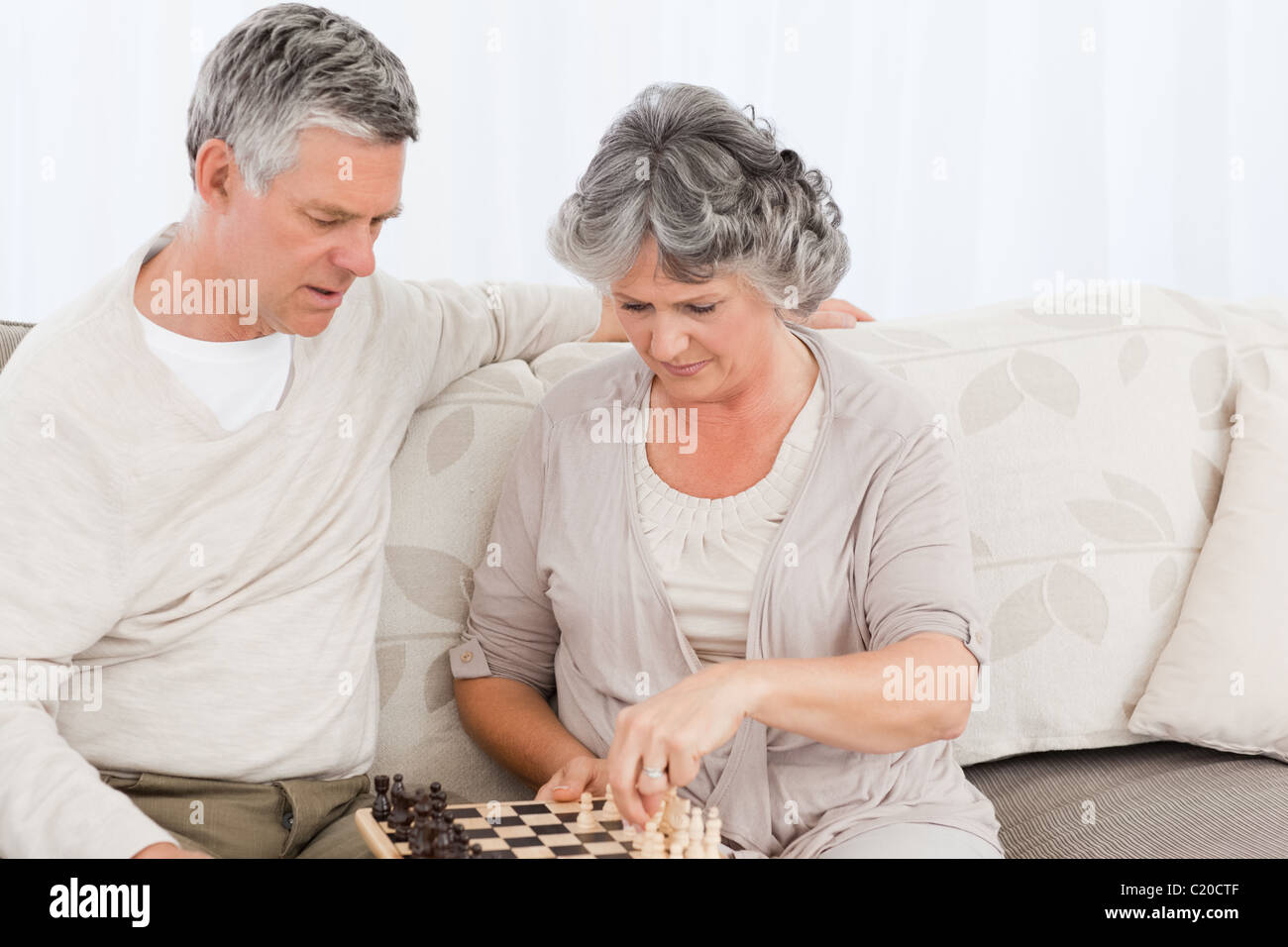 Couple playing chess on their sofa Stock Photo - Alamy