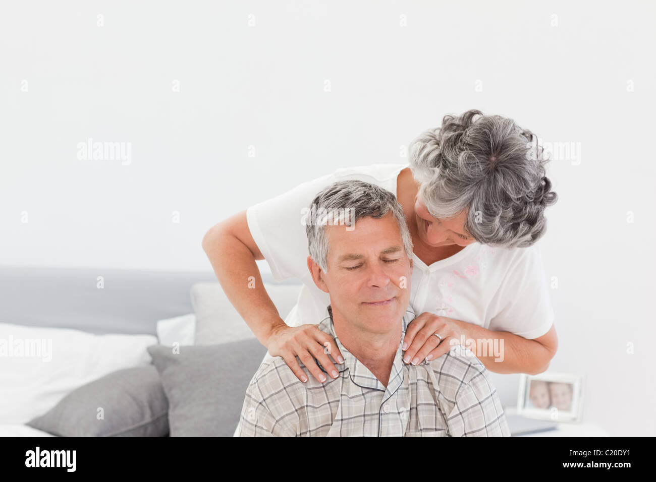 Retired woman giving a massage to her husband at home Stock Photo - Alamy