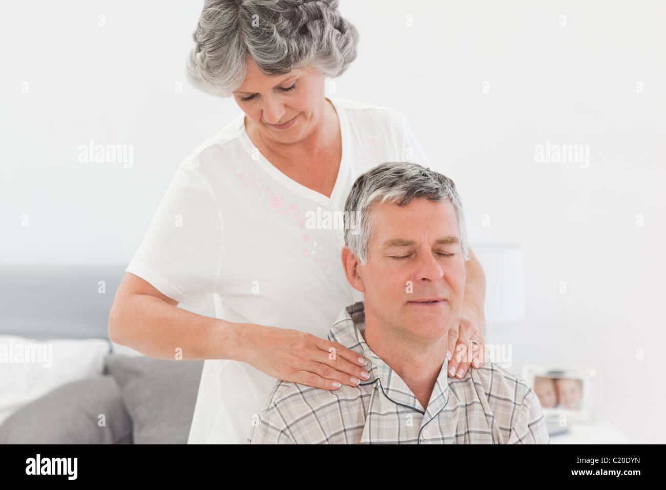 Retired woman giving a massage to her husband at home Stock Photo - Alamy