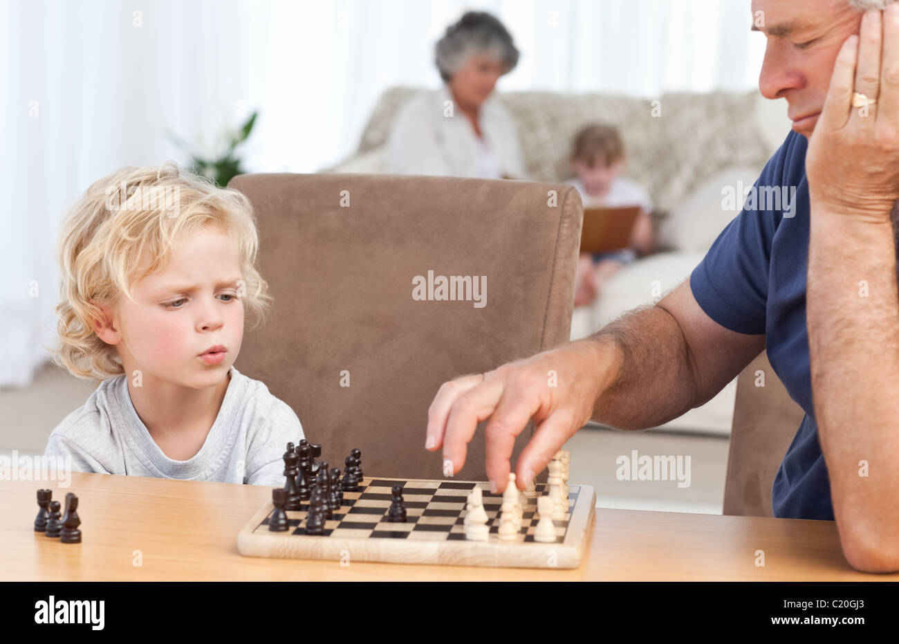 Young boy playing chess with his grandfather Stock Photo - Alamy