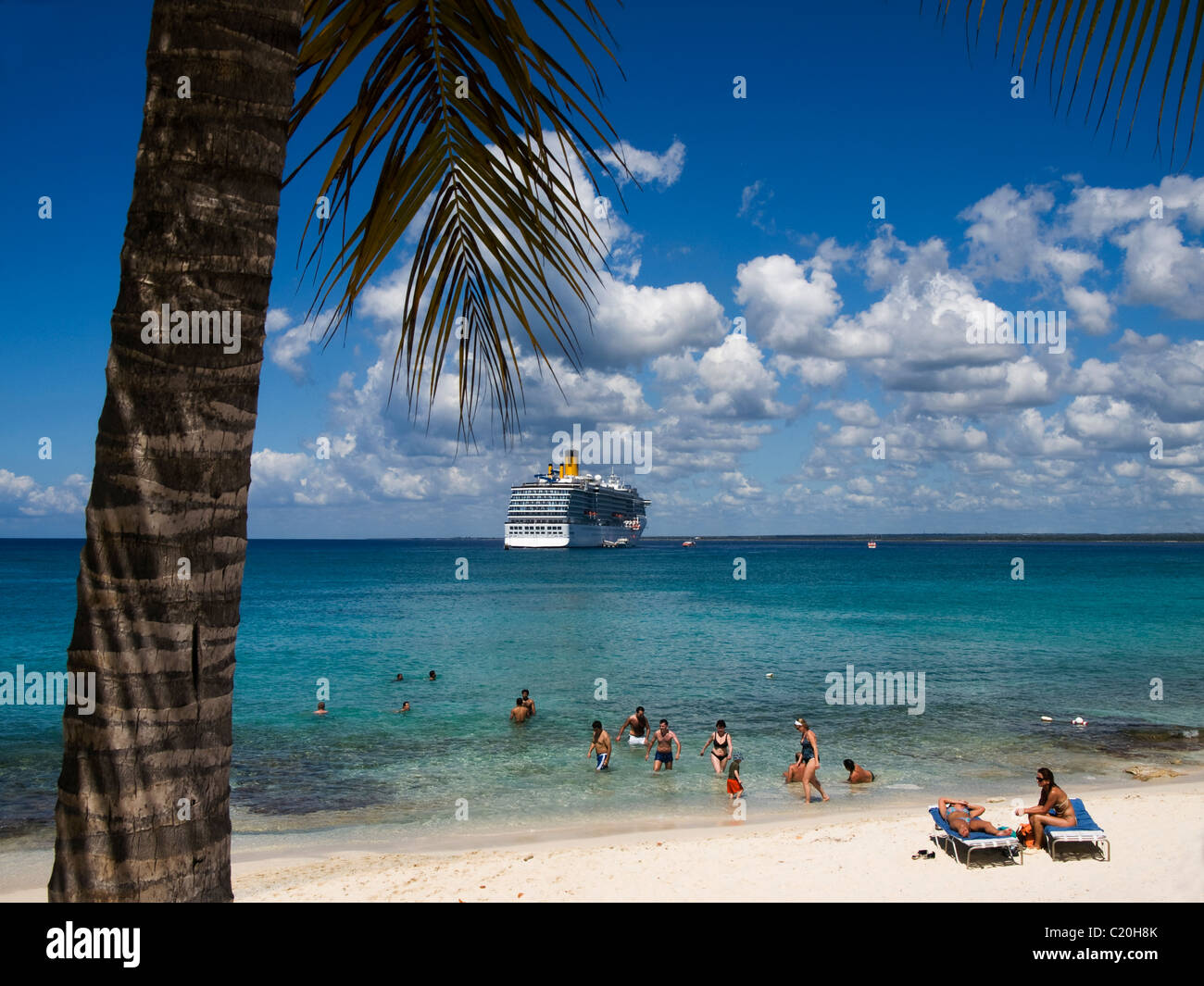 People sun bathing in the Caribbean with a cruise ship in the ...