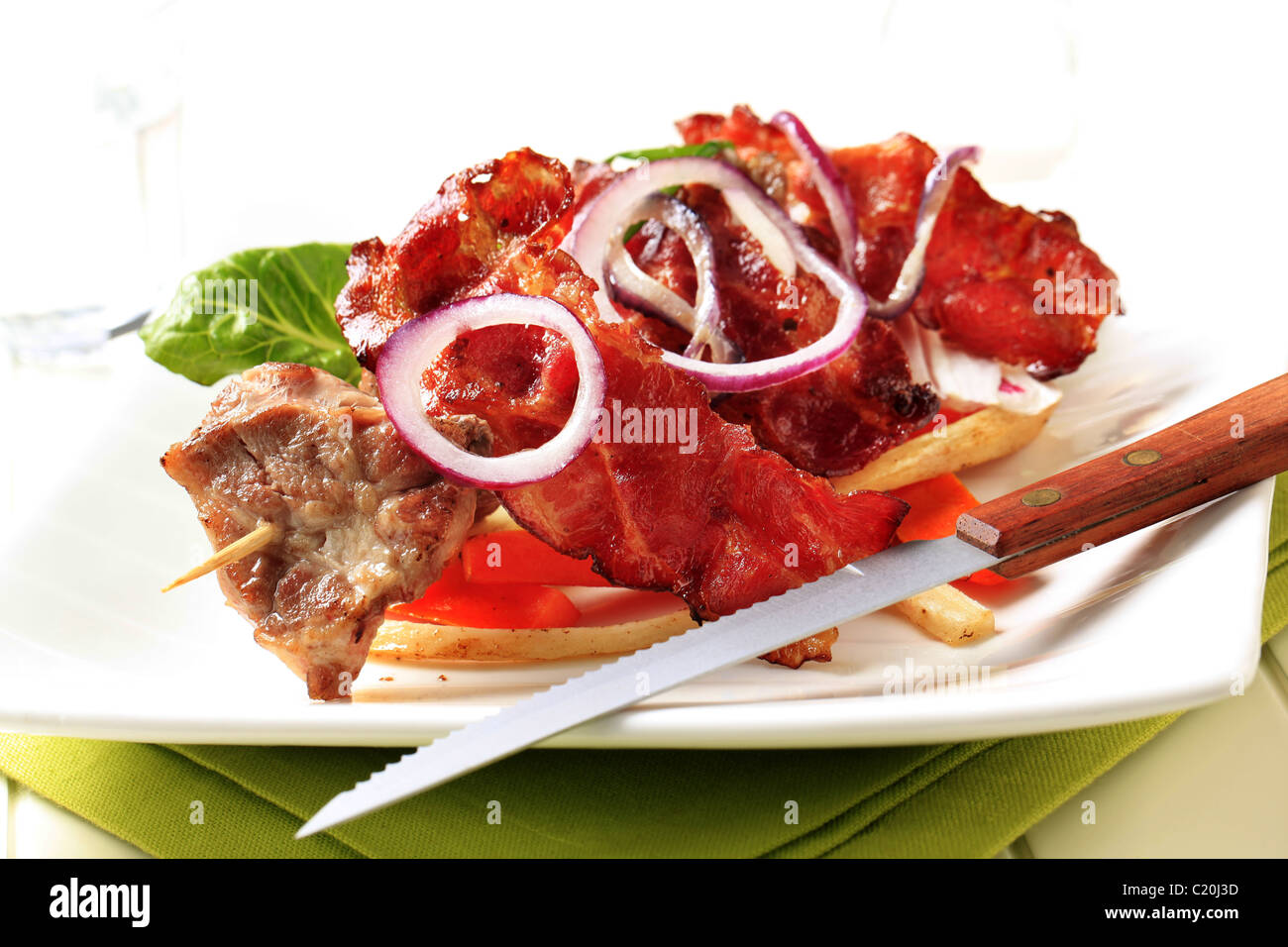 Shish kebab with crispy rashers of bacon and roasted vegetables Stock ...
