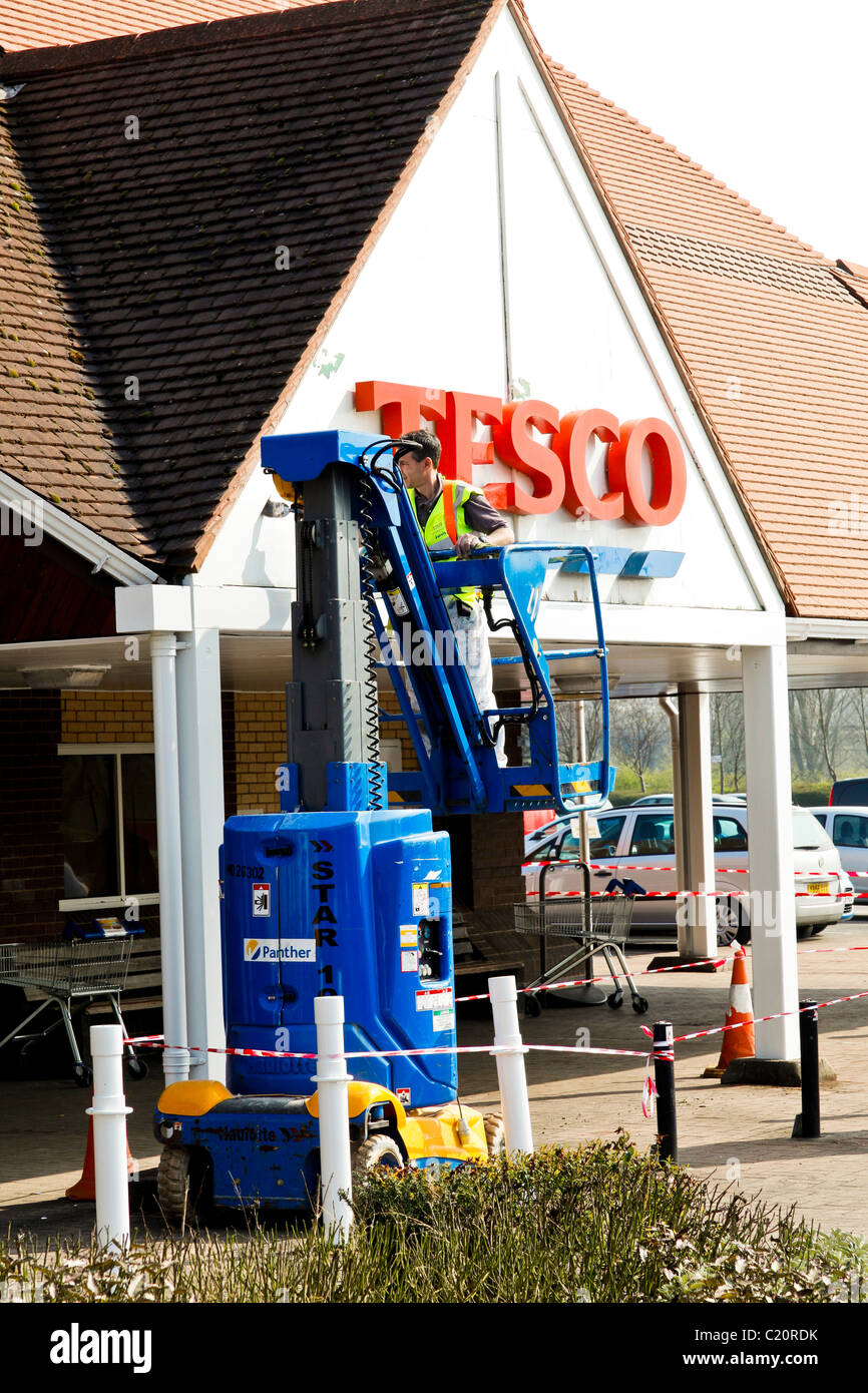 A painter at work on a Tesco supermarket building Stock Photo - Alamy