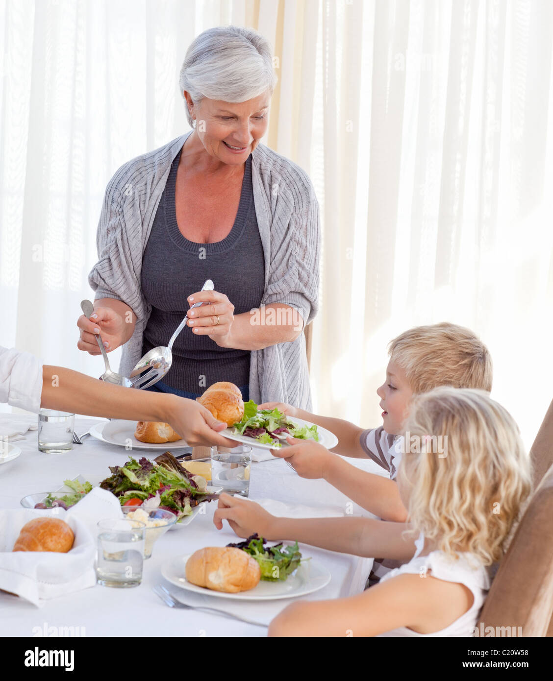 Grandmother giving other family members some food during the meal Stock ...