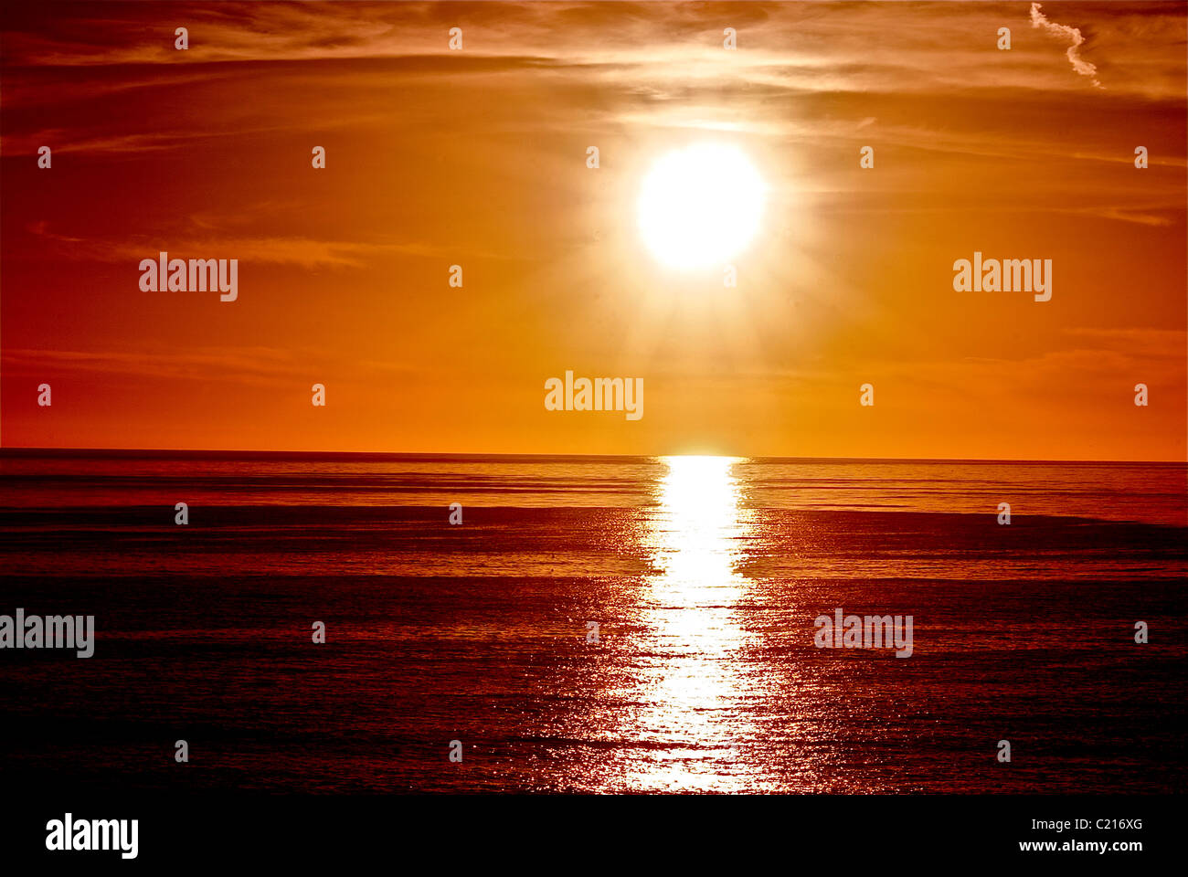 A orange sunset shining and reflecting over the ocean Stock Photo - Alamy