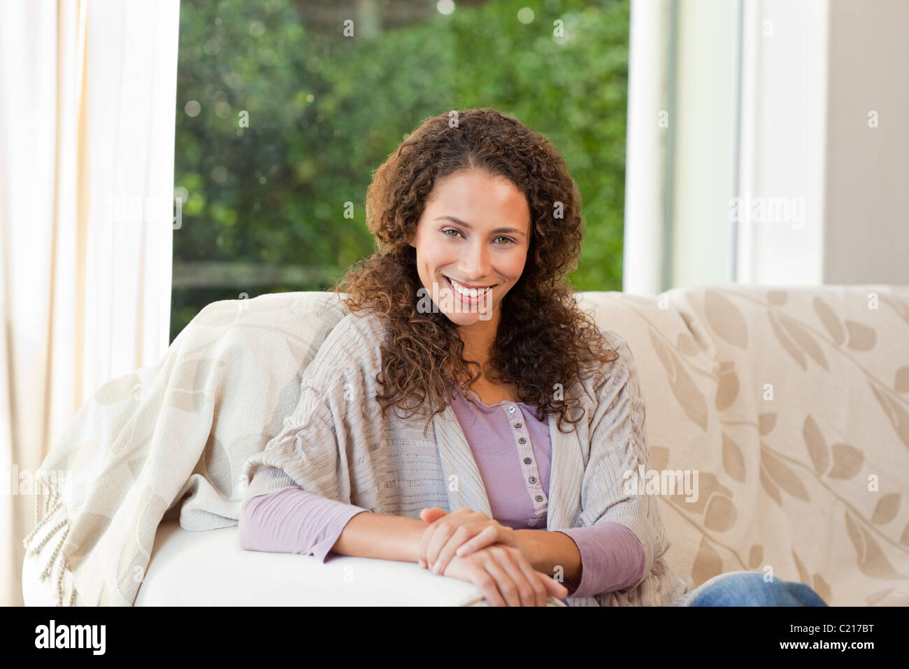 Smiling woman sitting on her sofa Stock Photo - Alamy