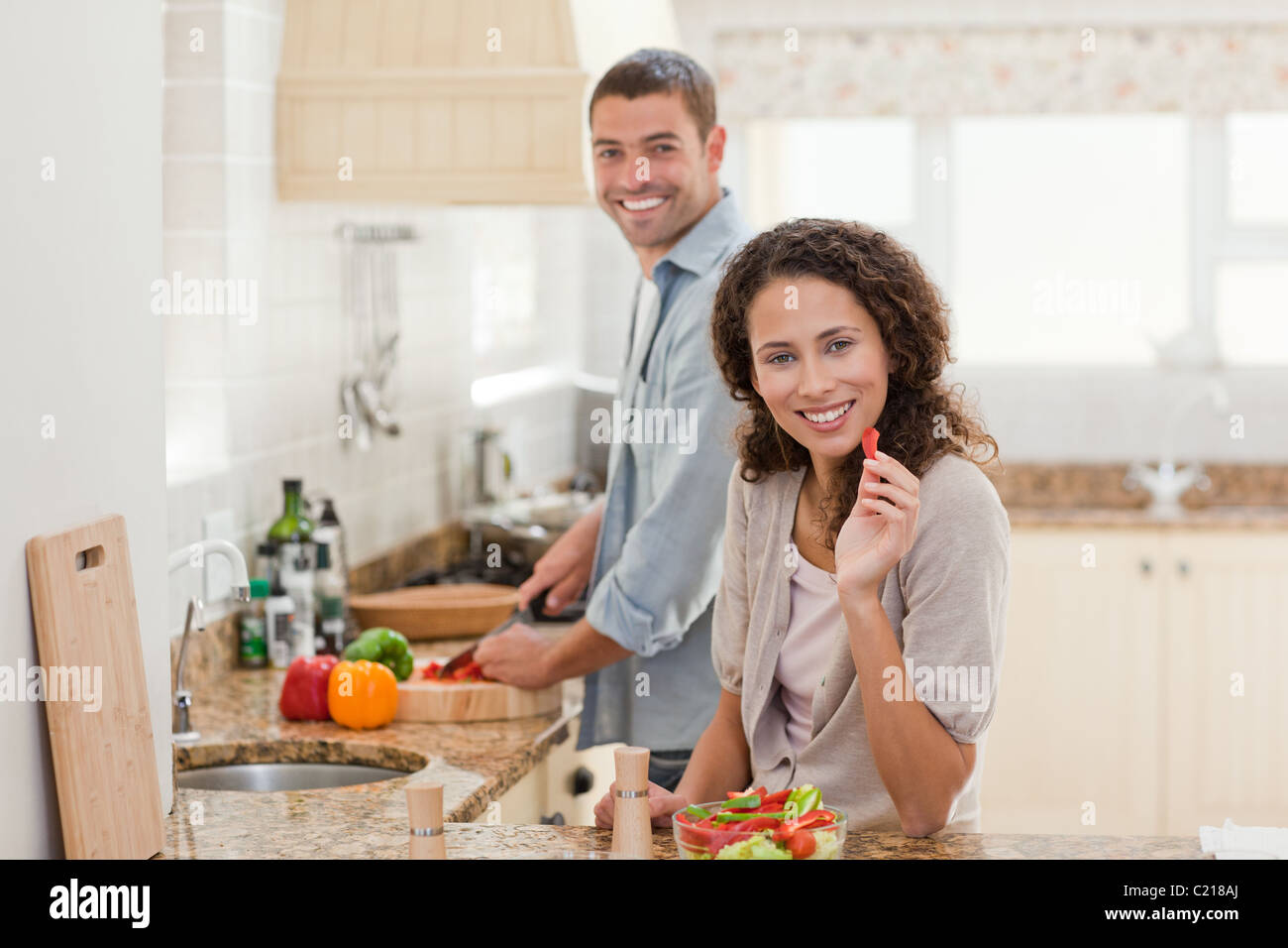 Woman eating while her husband is cooking Stock Photo - Alamy
