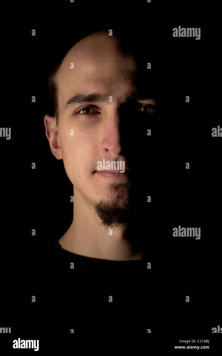 Low key studio portrait of young handsome man over black background ...