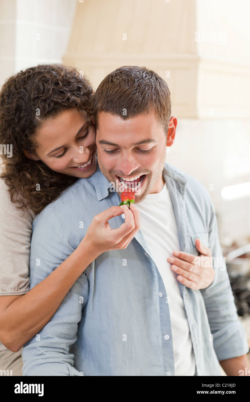 Lovers eating a strawberry in their kitchen Stock Photo - Alamy