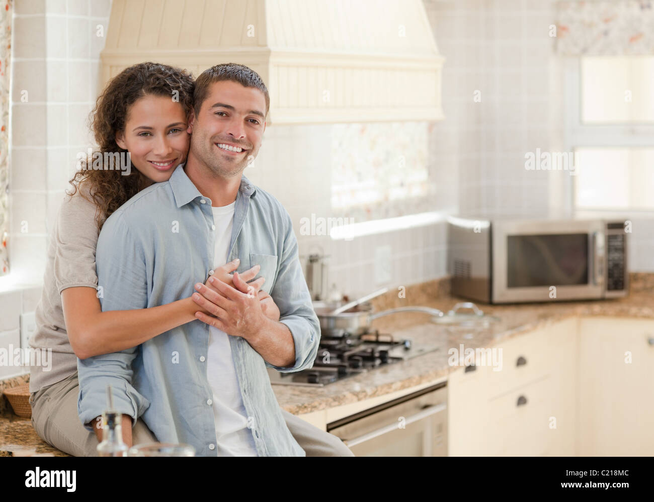 Beautiful couple hugging in the kitchen Stock Photo - Alamy