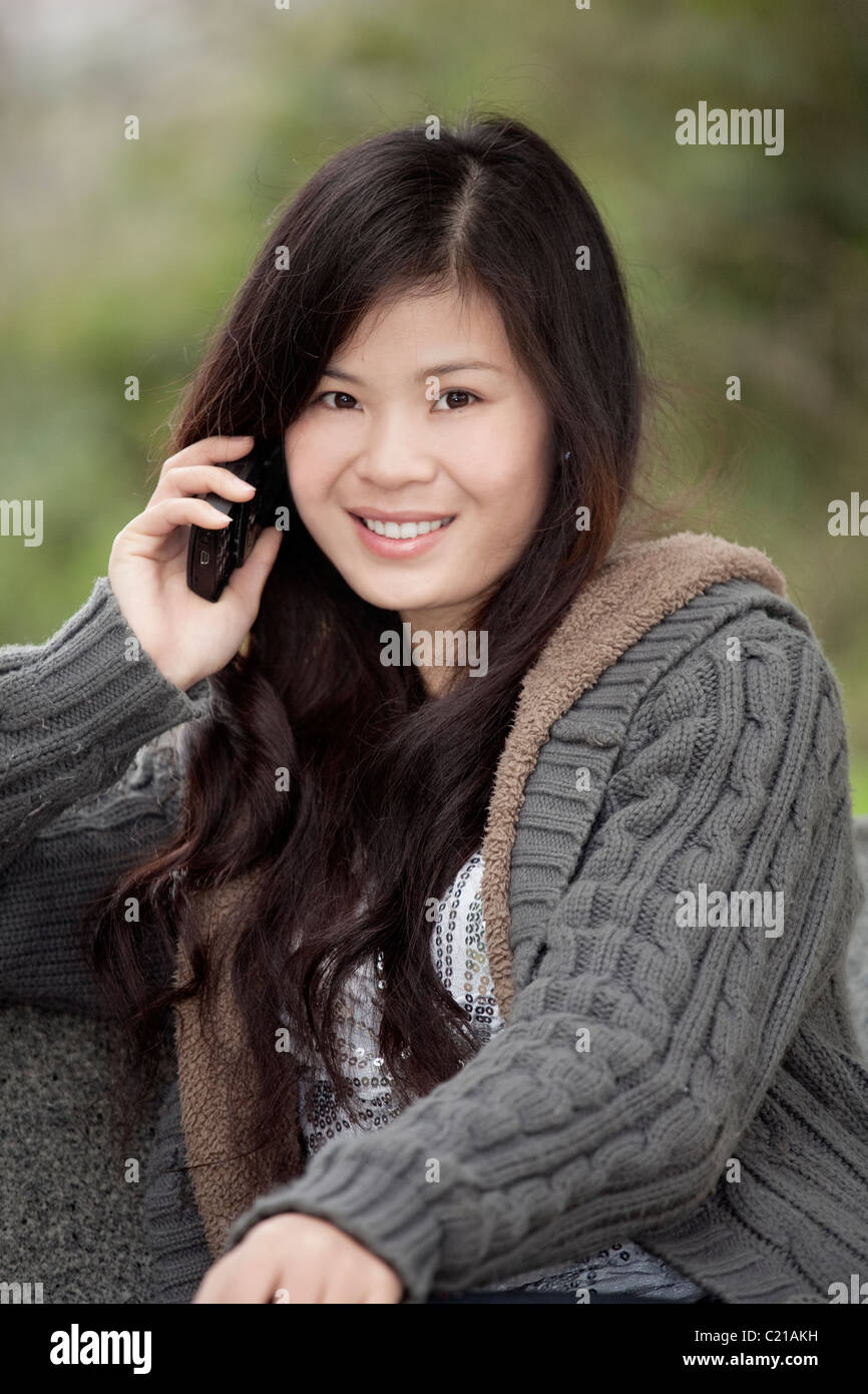 Beautiful Chinese Woman using a cell phone outdoors Stock Photo - Alamy