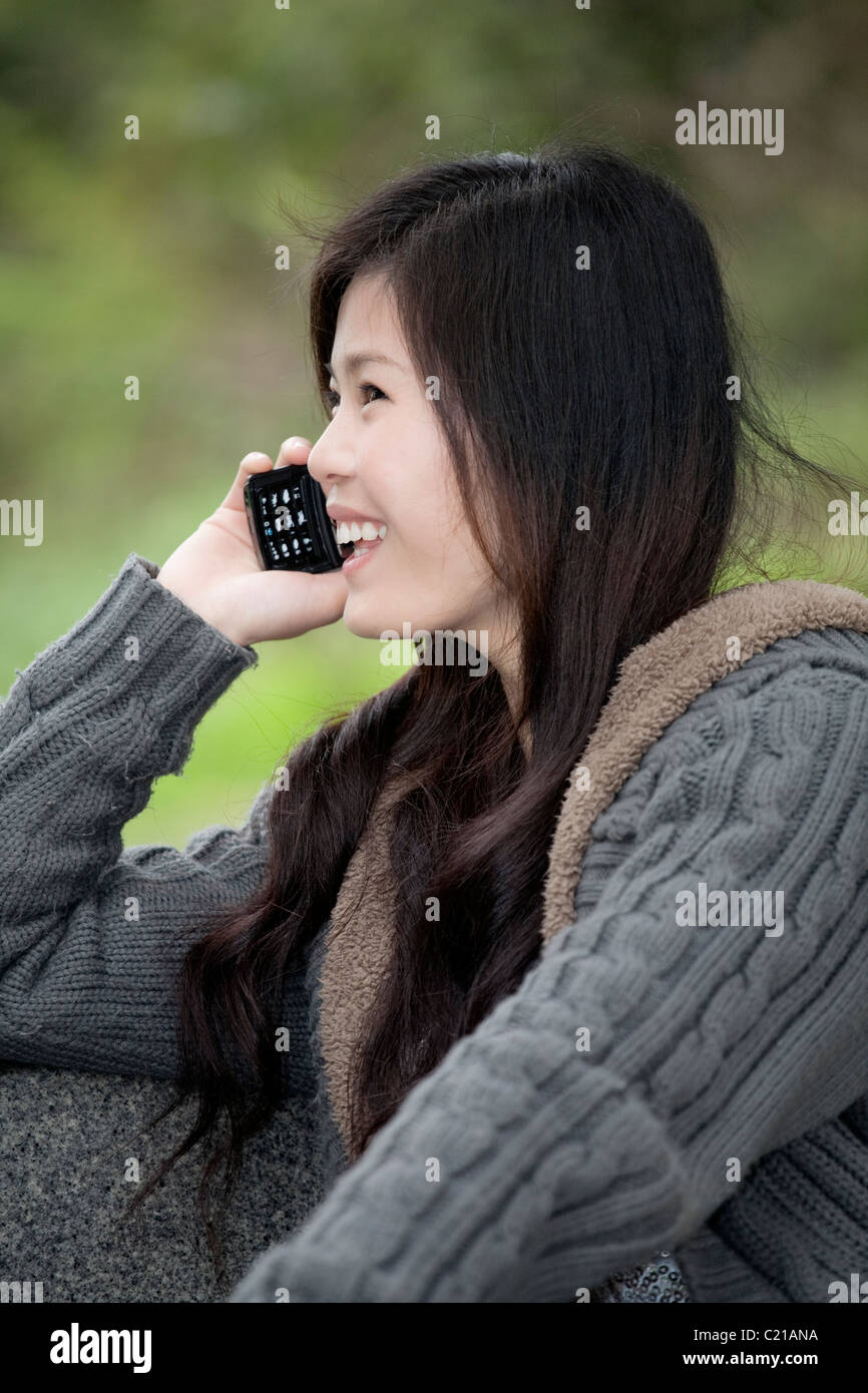 Beautiful Chinese Woman using a cell phone outdoors Stock Photo - Alamy